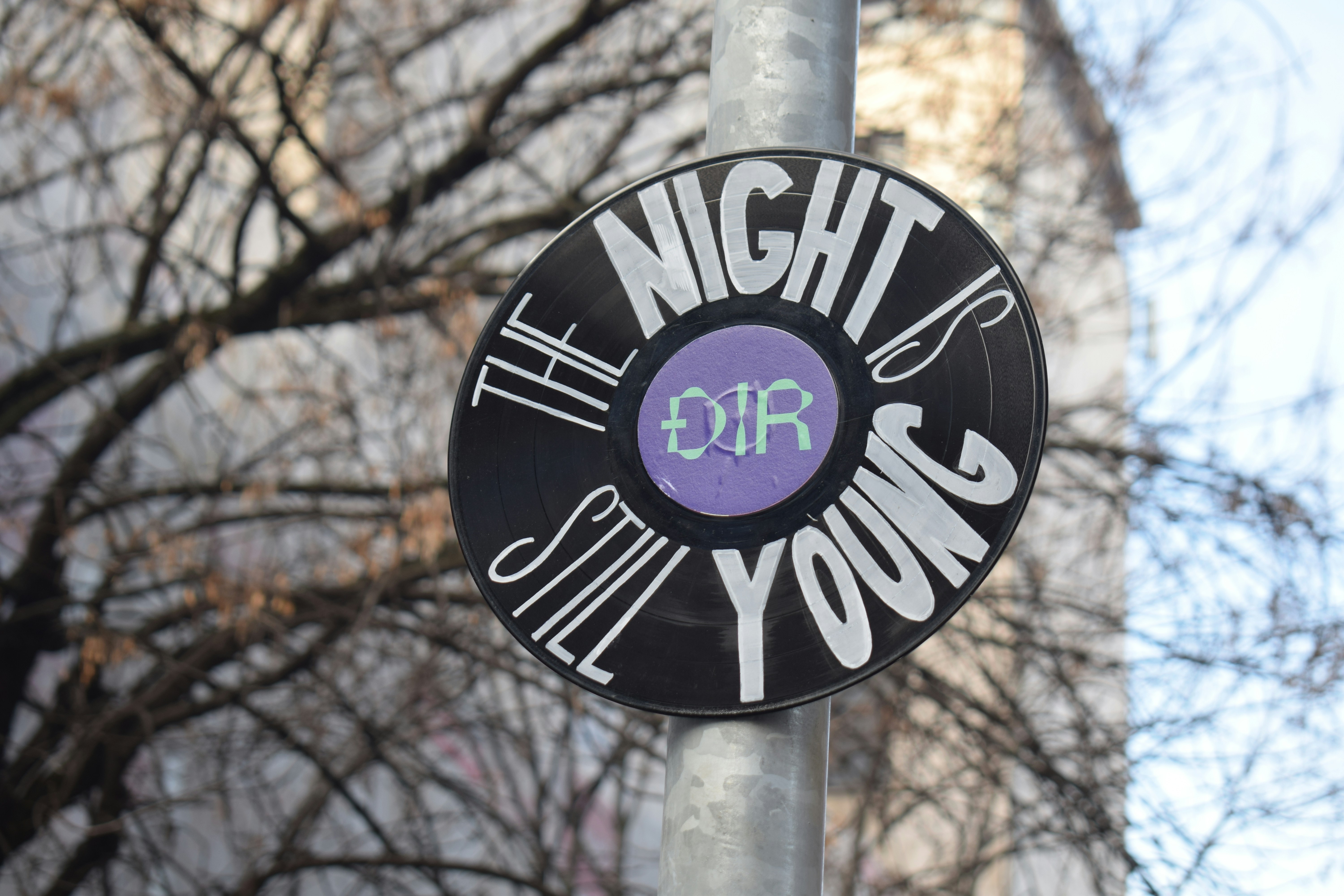 Night Still Young: A Neon-Painted Circle on a City Lamp Post