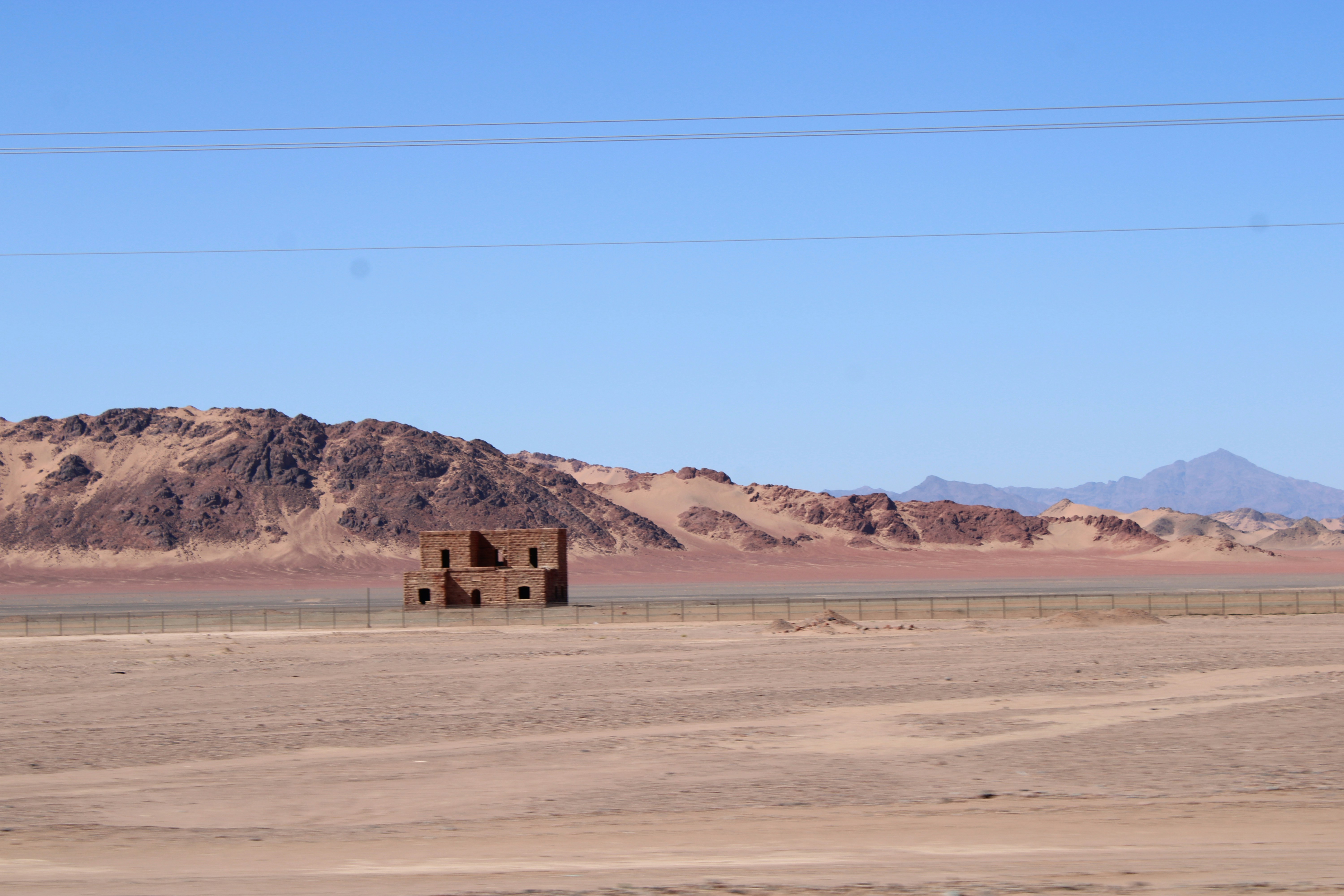 Dusty Fort in the Dunes: A Lonely Brick House Against an Expansive Desert