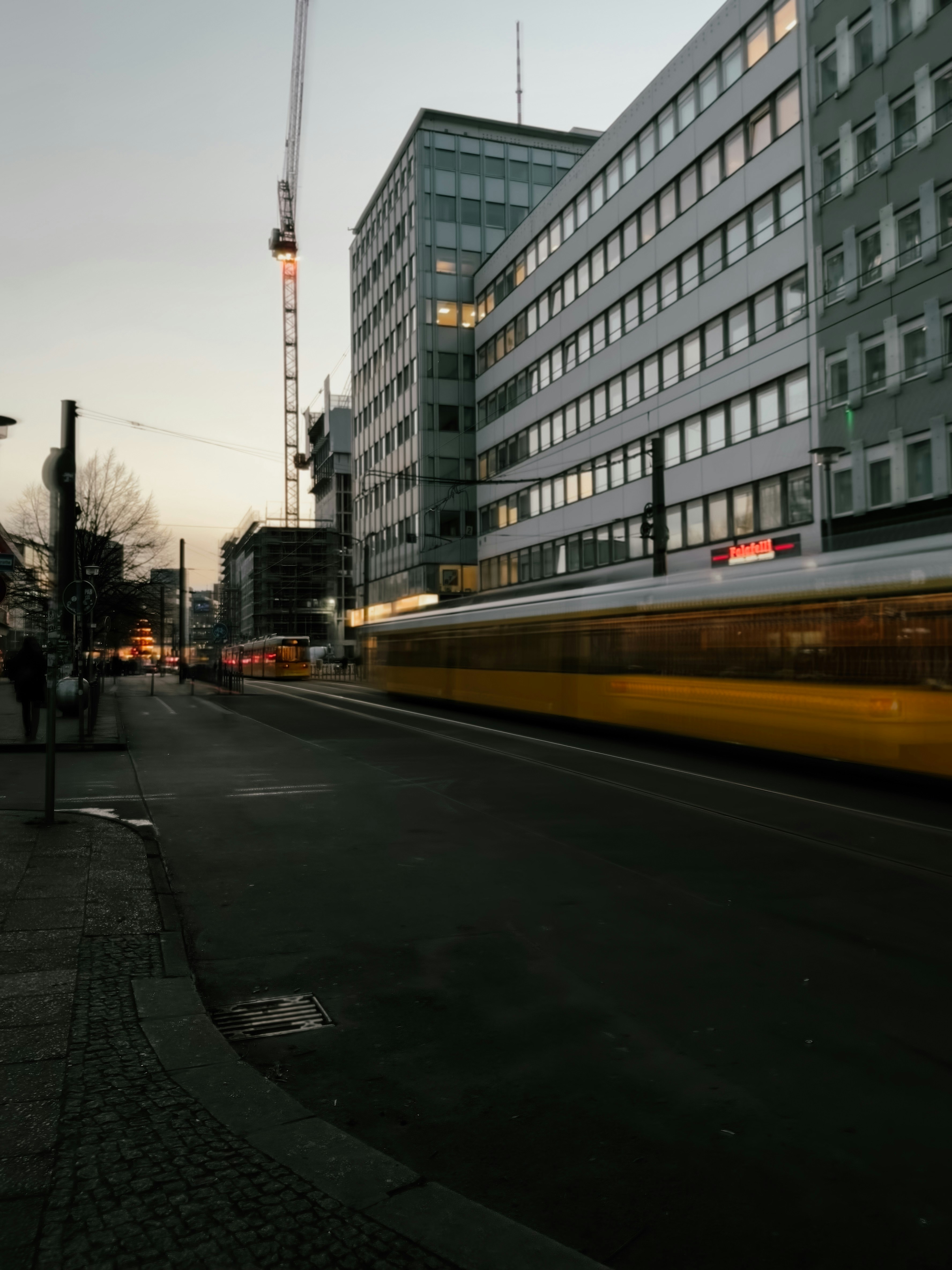 A yellow tram moves quickly down a city street.Maria Molnarova