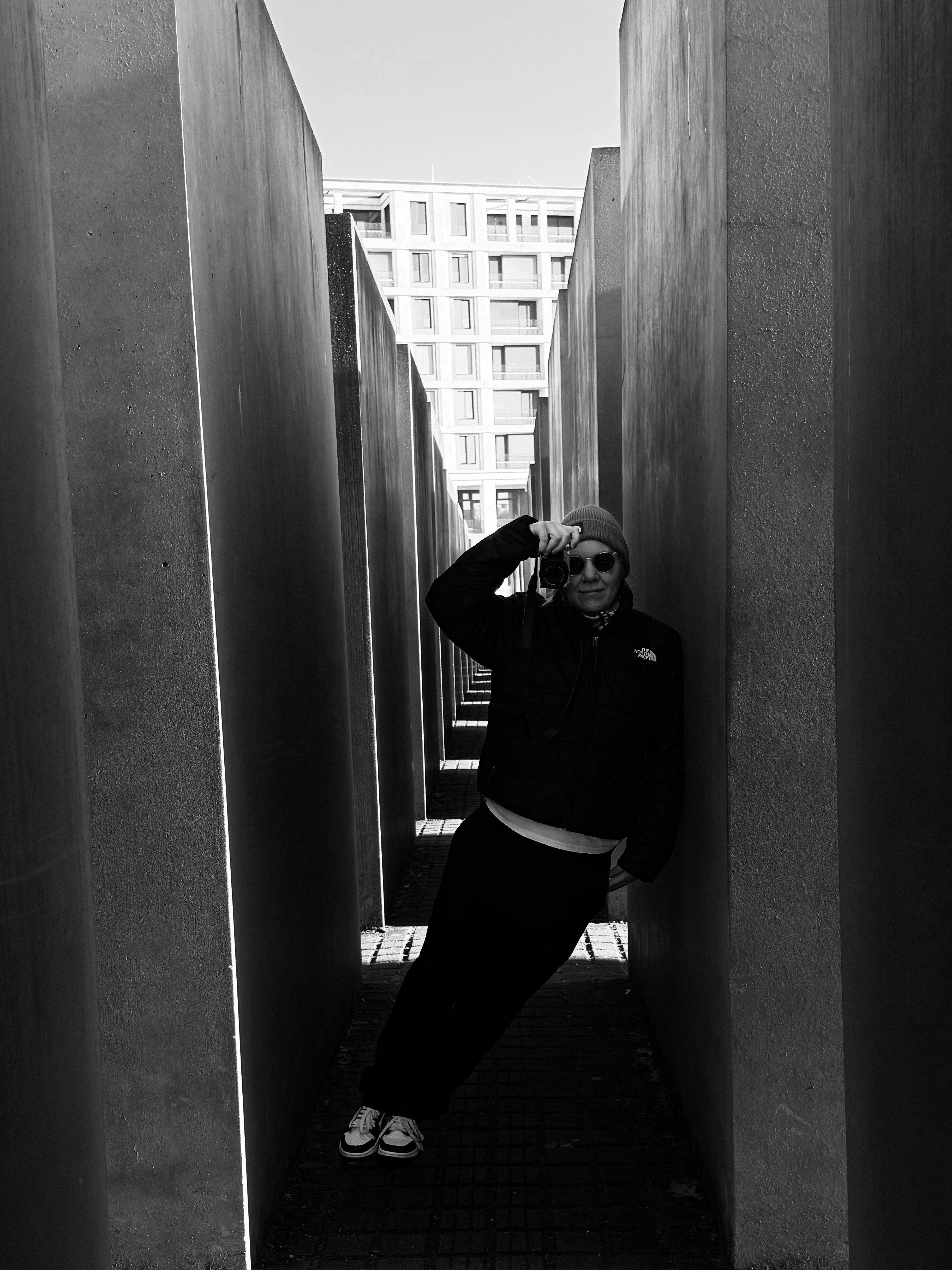 A person stands between tall concrete blocks holding a camera.Maria Molnarova