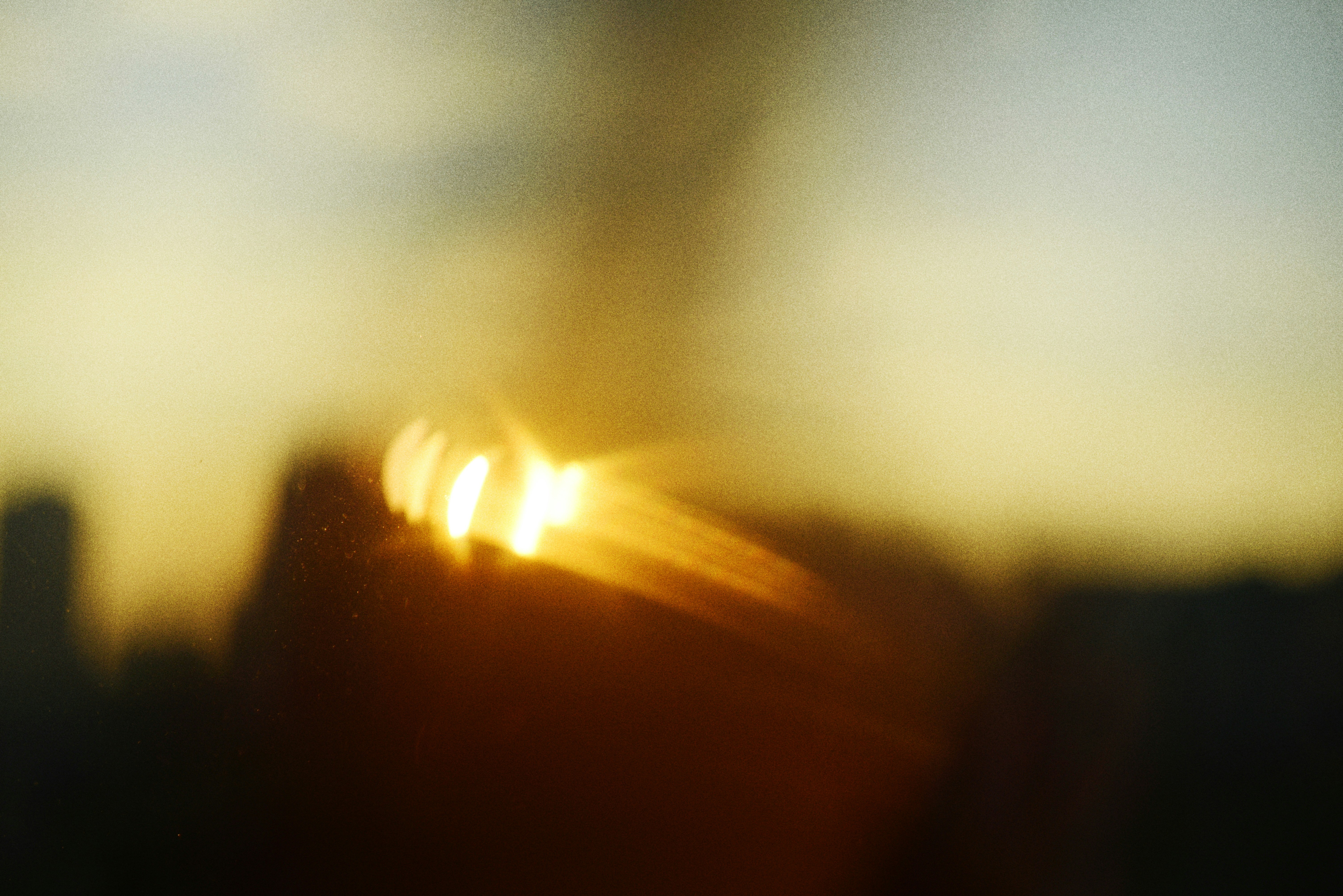 Blurred sunset with light rays over dark landscape.