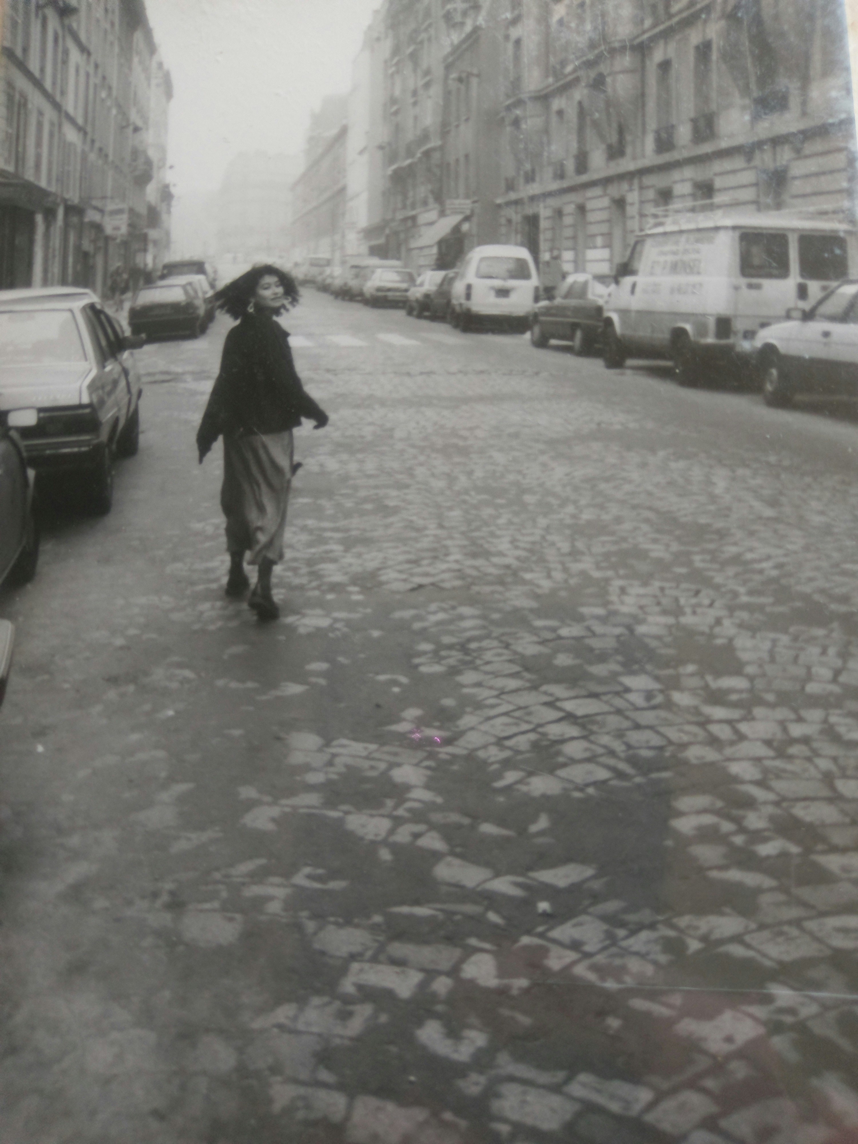 Woman walking down a cobblestone street in paris.