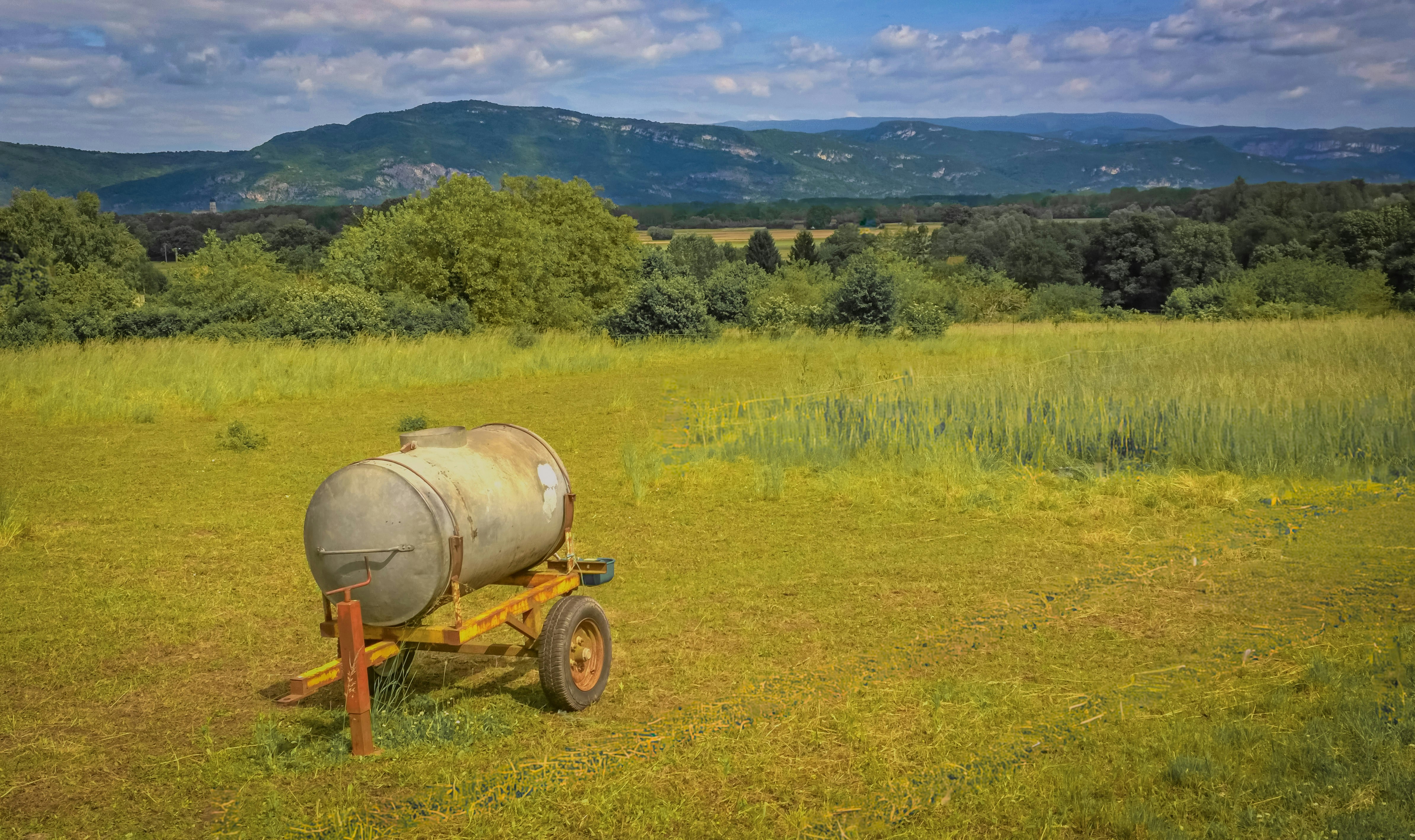 Water tank on wheels in a grassy field.