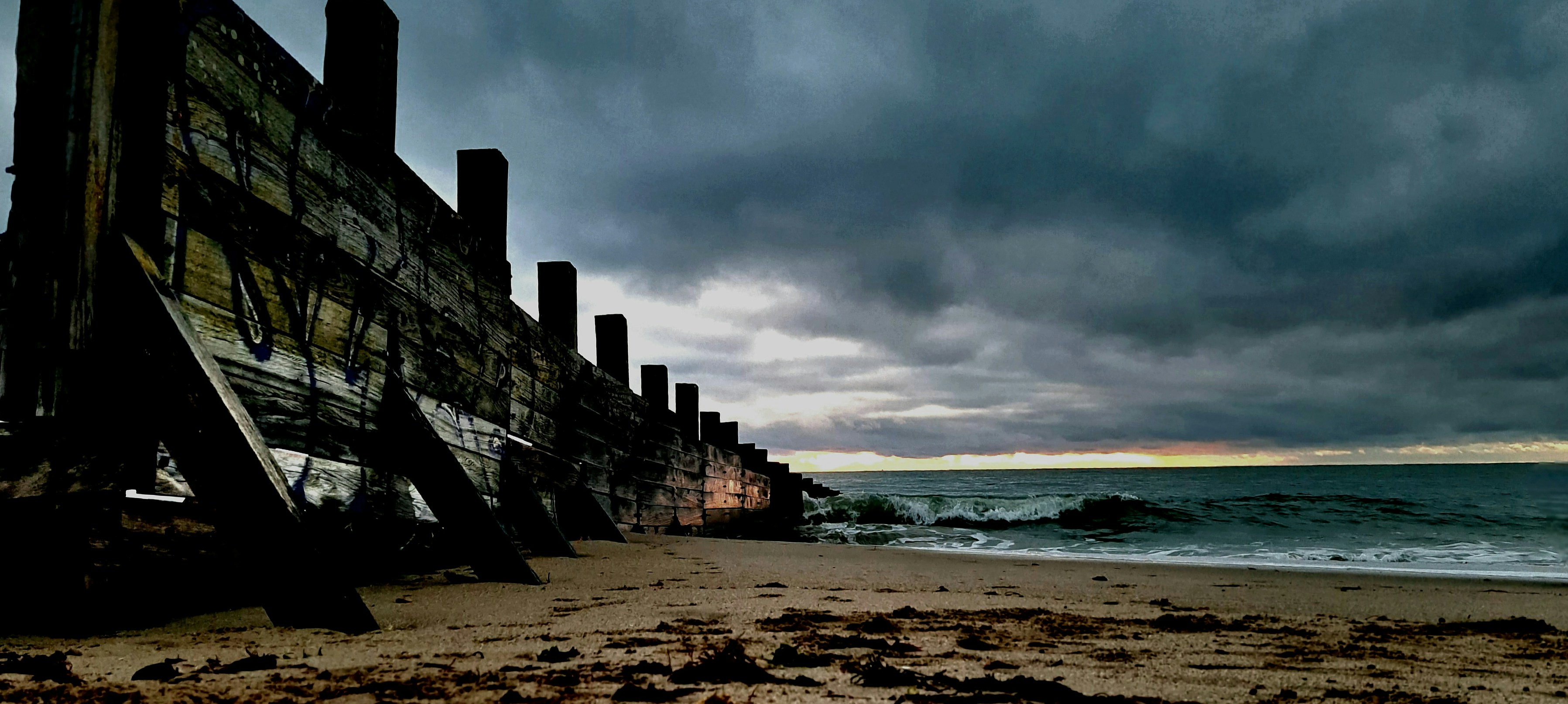 Wooden sea defense on a beach with stormy clouds. photo – Free Beach ...
