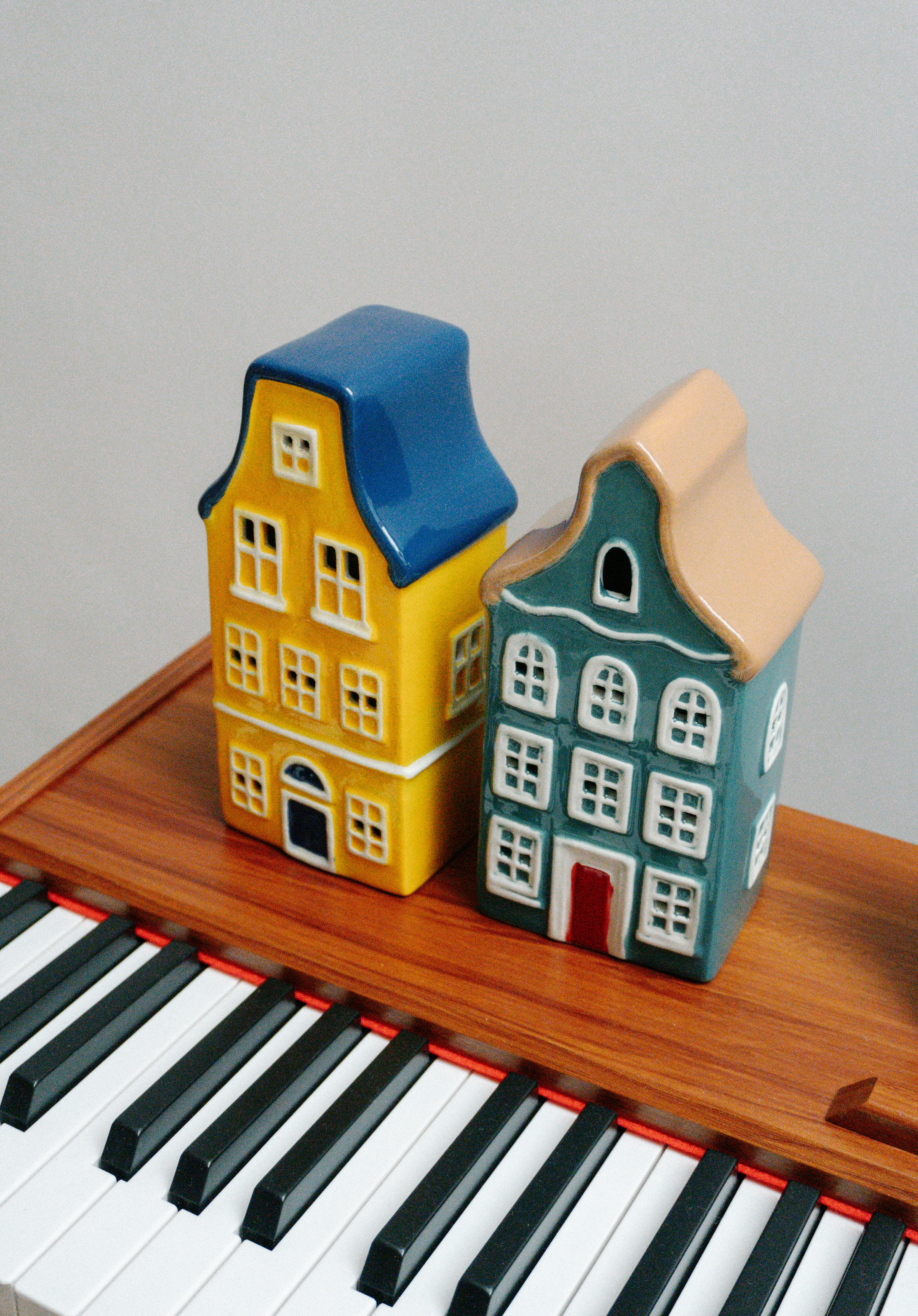 Toy houses on a wooden piano edge, captured with warm whimsy
