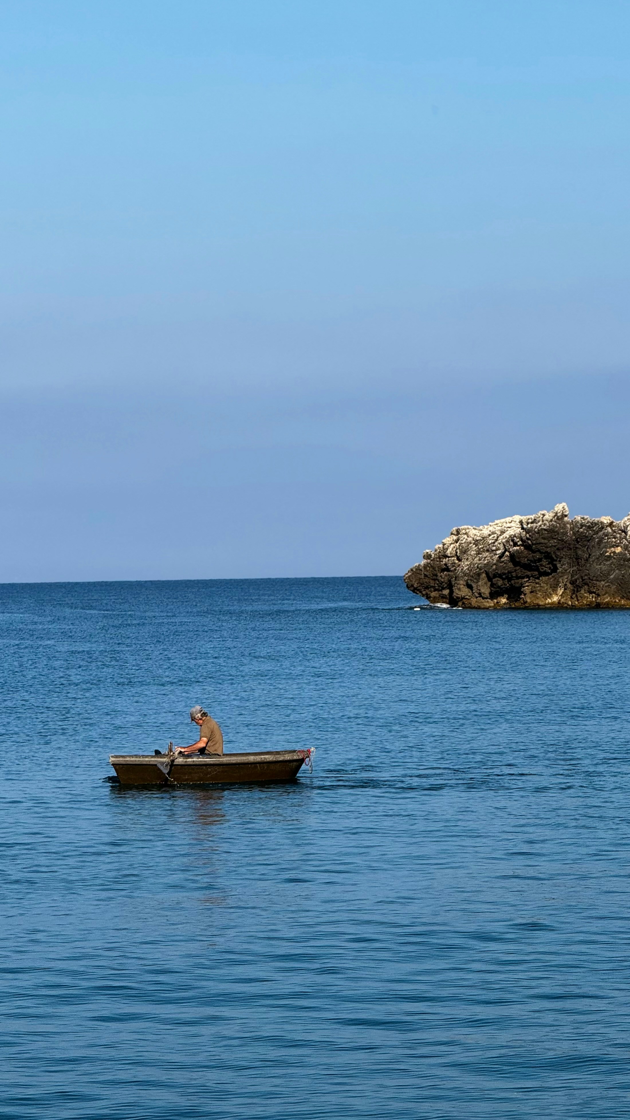 A solitary rower drifts through calm blue horizons