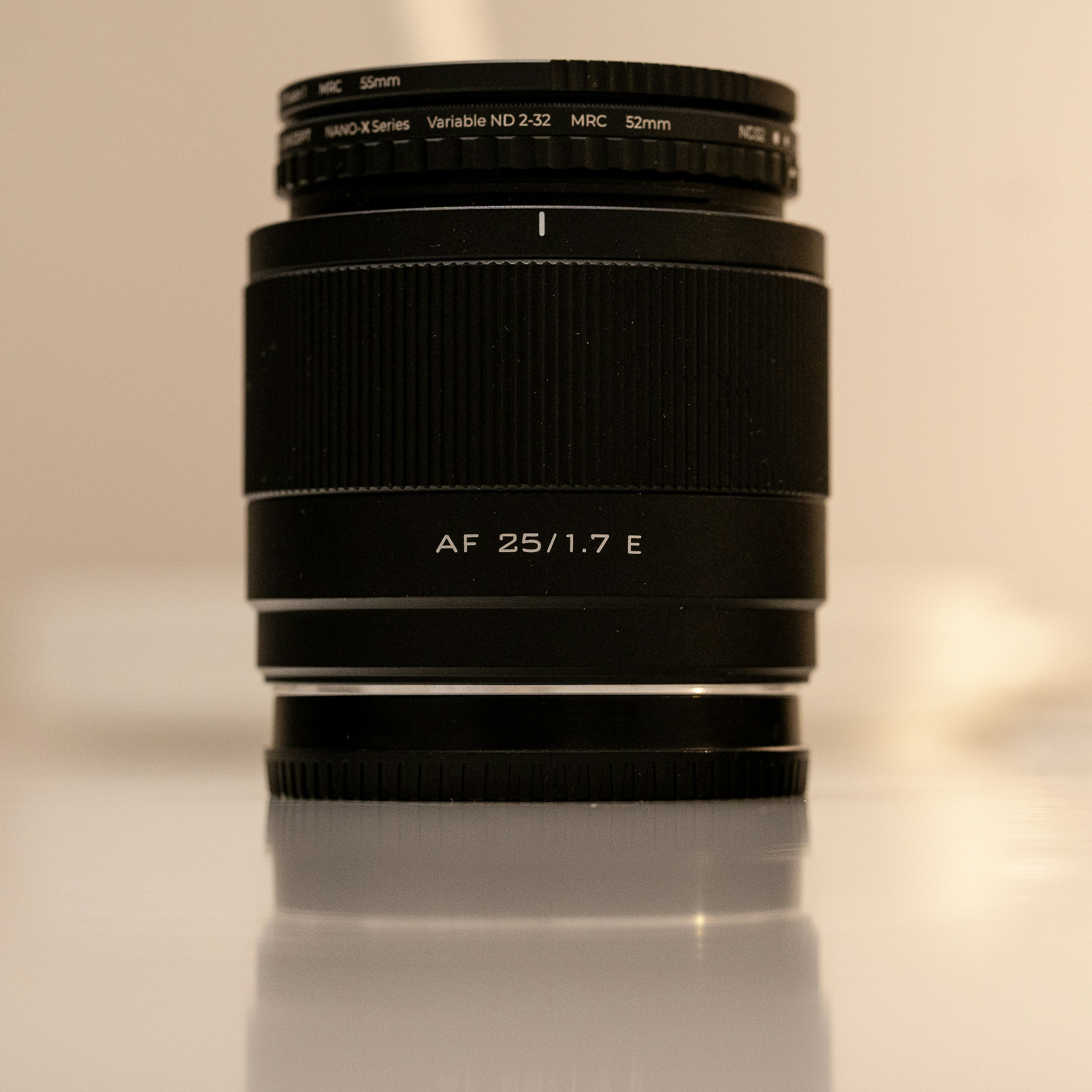 Portrait of a Prime: A close-up of a 25mm f/1.7 prime lens resting on a reflective surface