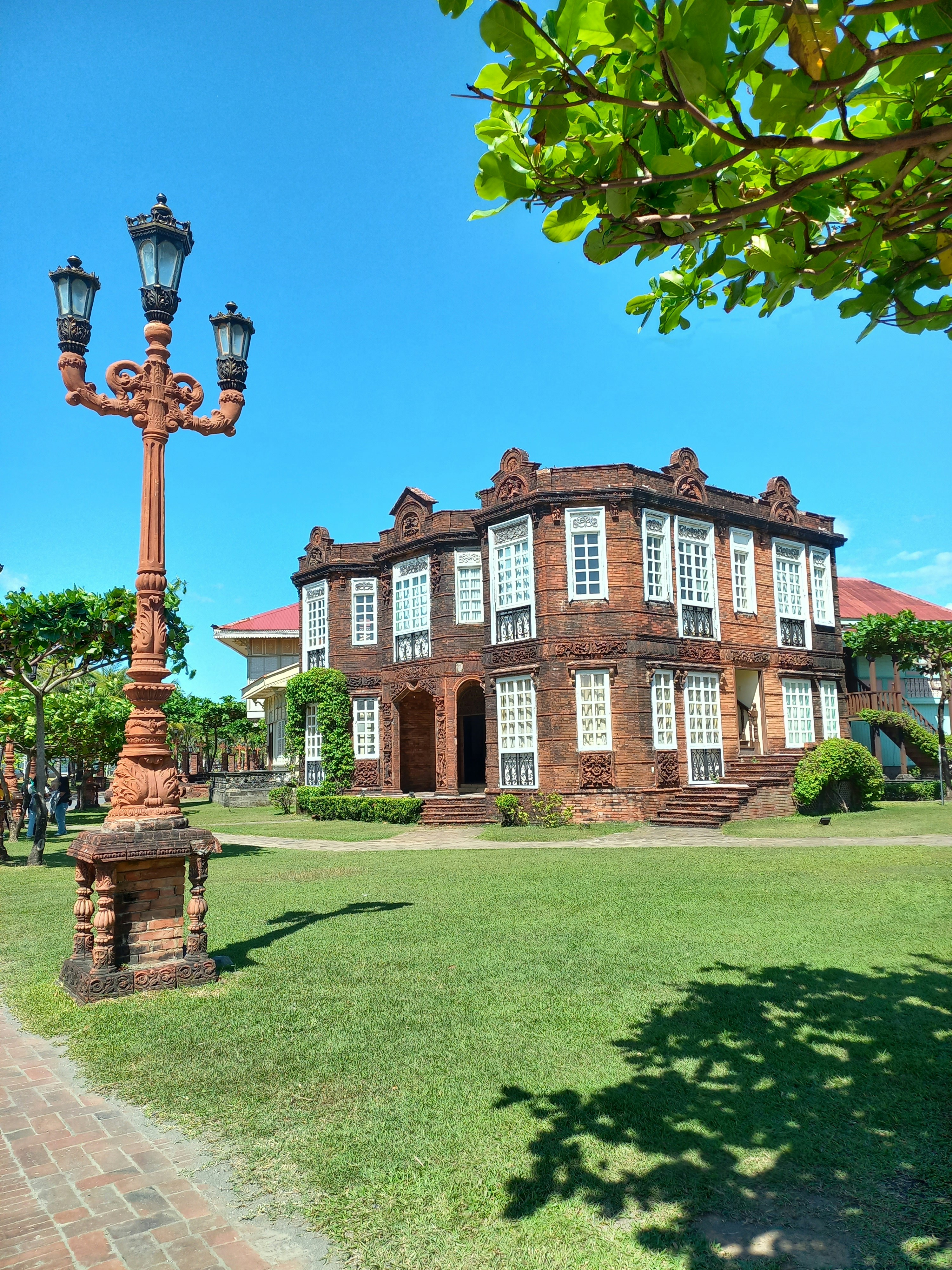Historic brick building with ornate lamppost on lawn