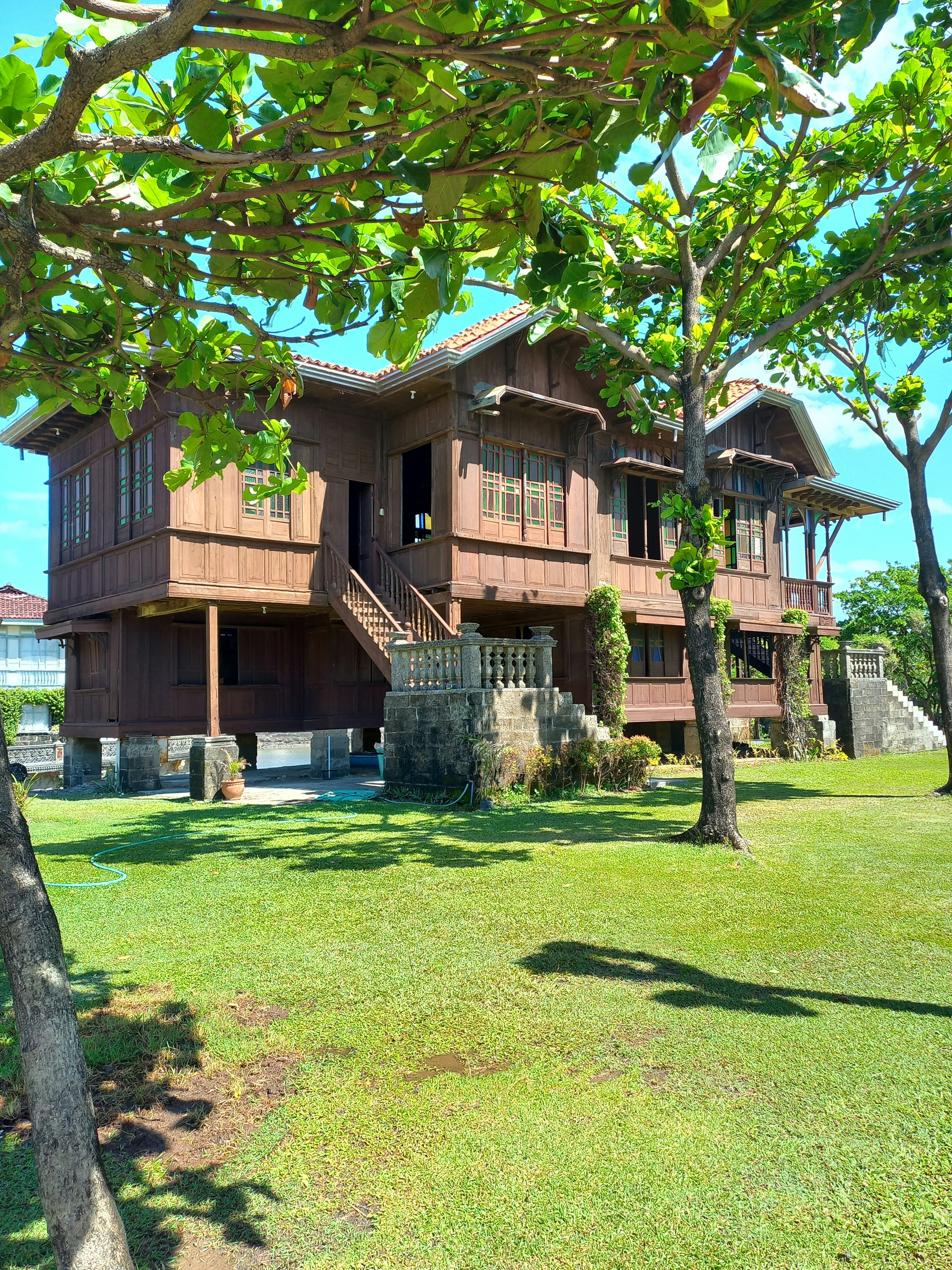 Traditional wooden house on grassy lawn with trees