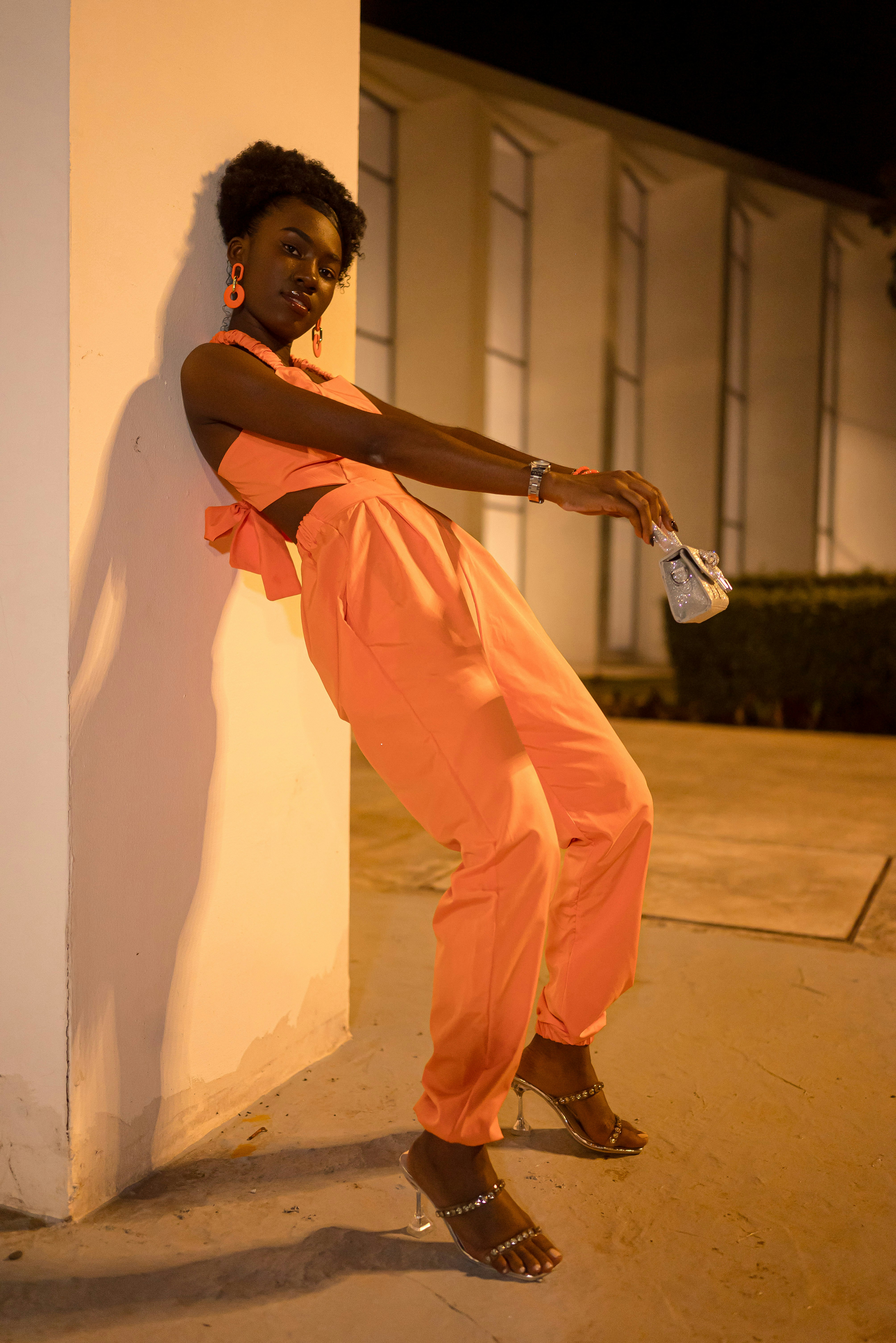 Sunlit Pose in Coral Attire: Nightscape Fashion at the Corner Pillar
