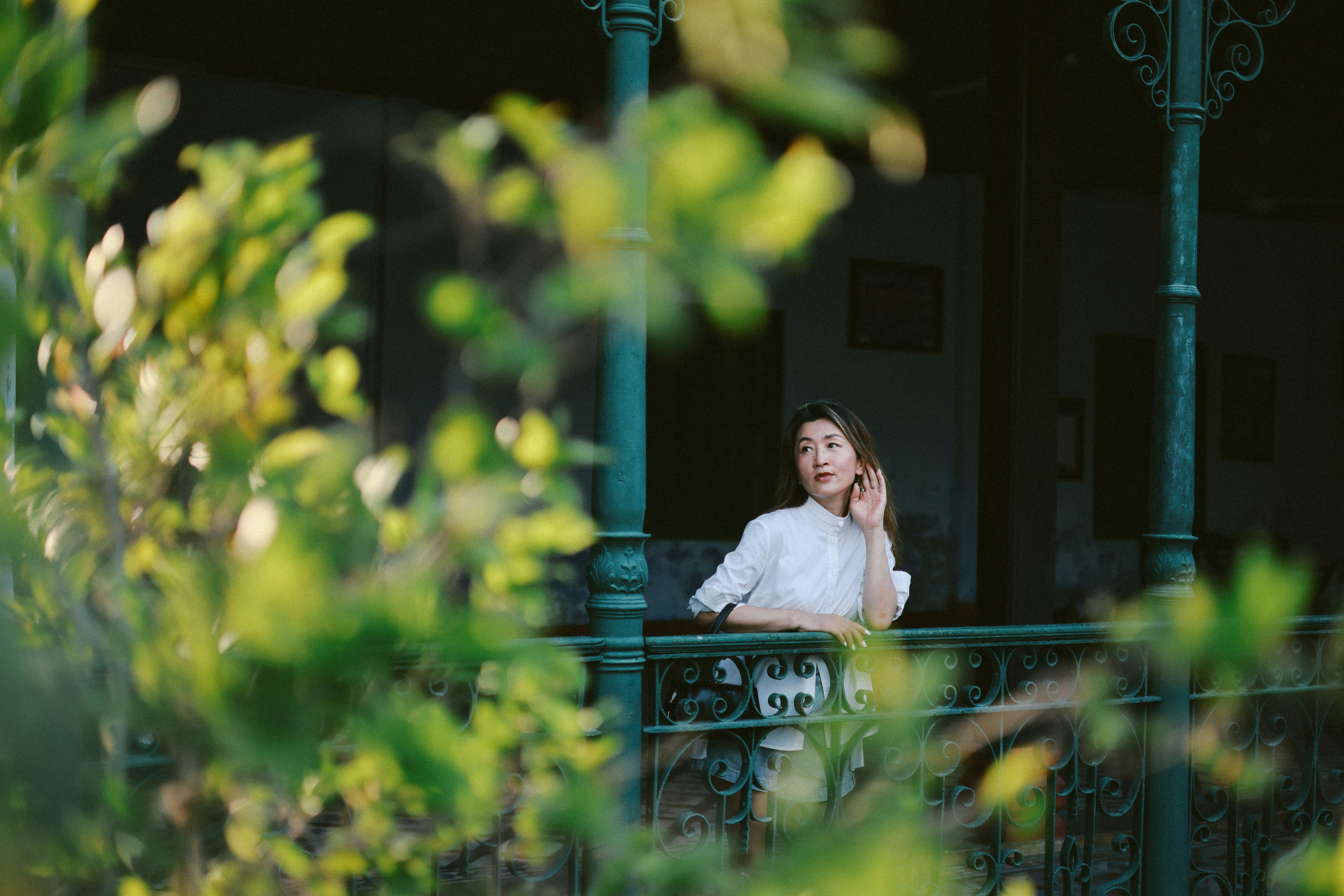 Portrait on a Green Terrace: A Quiet Gaze Through Ornate Rails