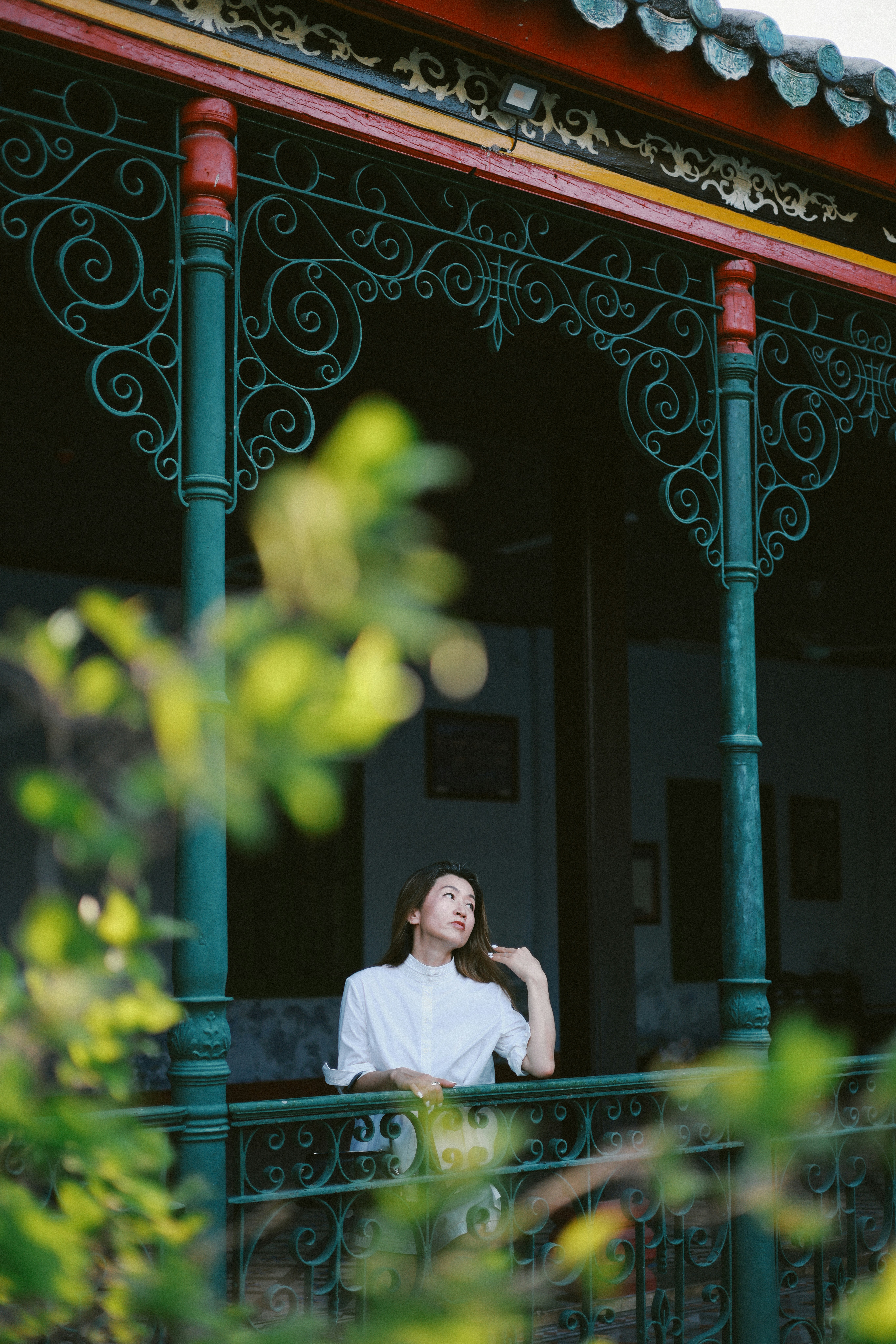 Portrait on a Painted Veranda: Quiet Confidence Beneath Ornate Fronds