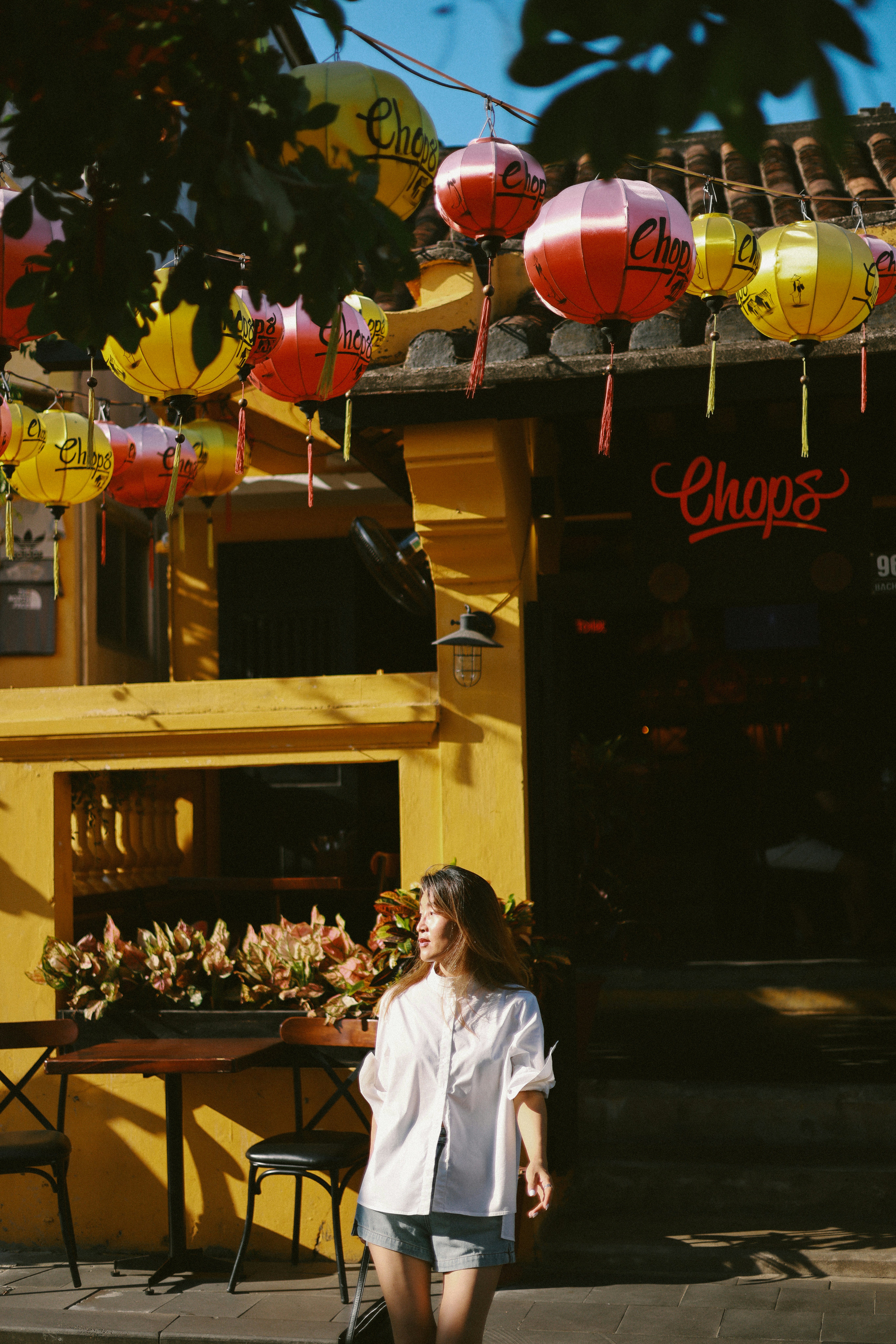 Sunlit Streetwear: A Woman Beneath Colorful Lanterns