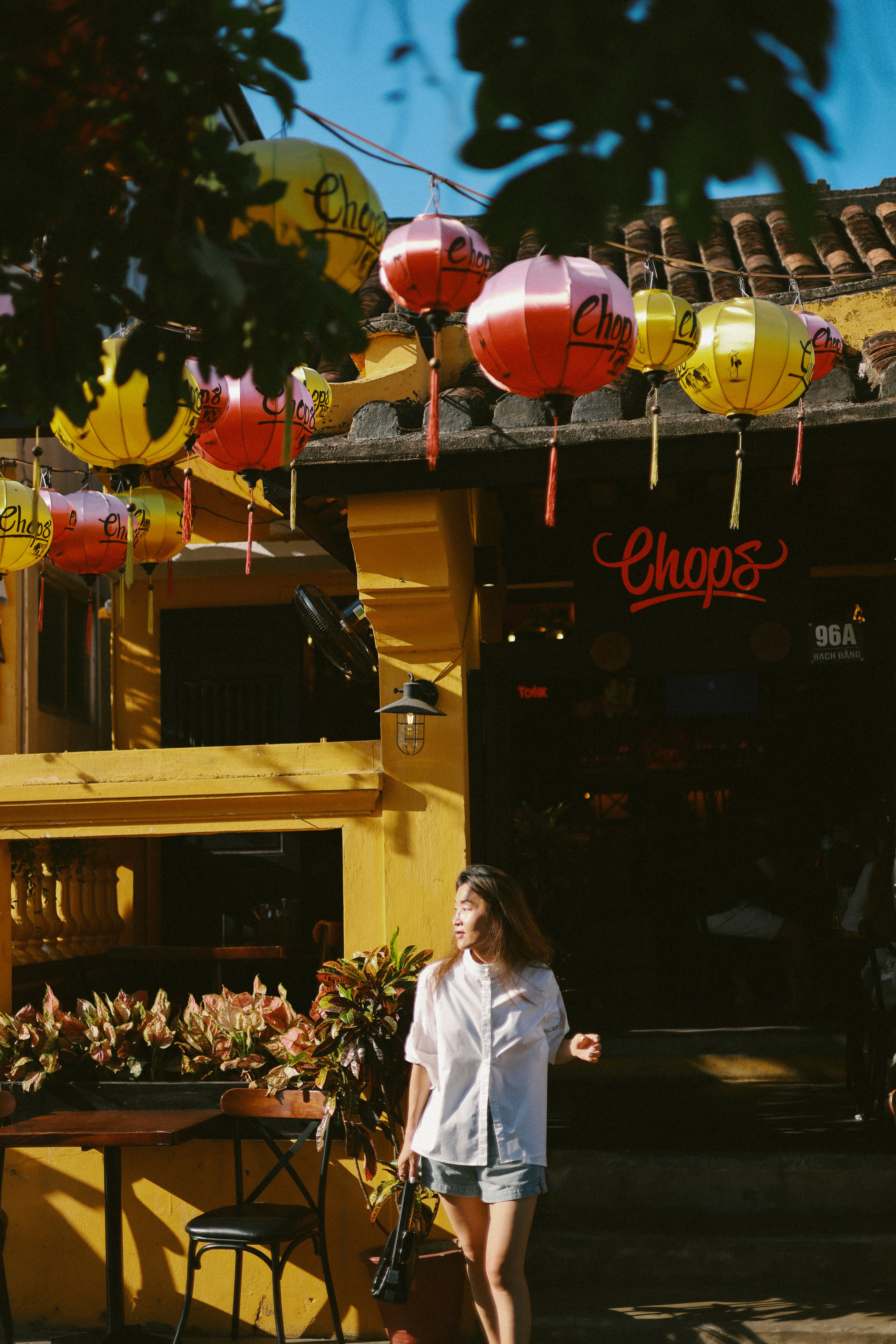 Sunlit Street Style: A Quiet Moment Under Colorful Lanterns