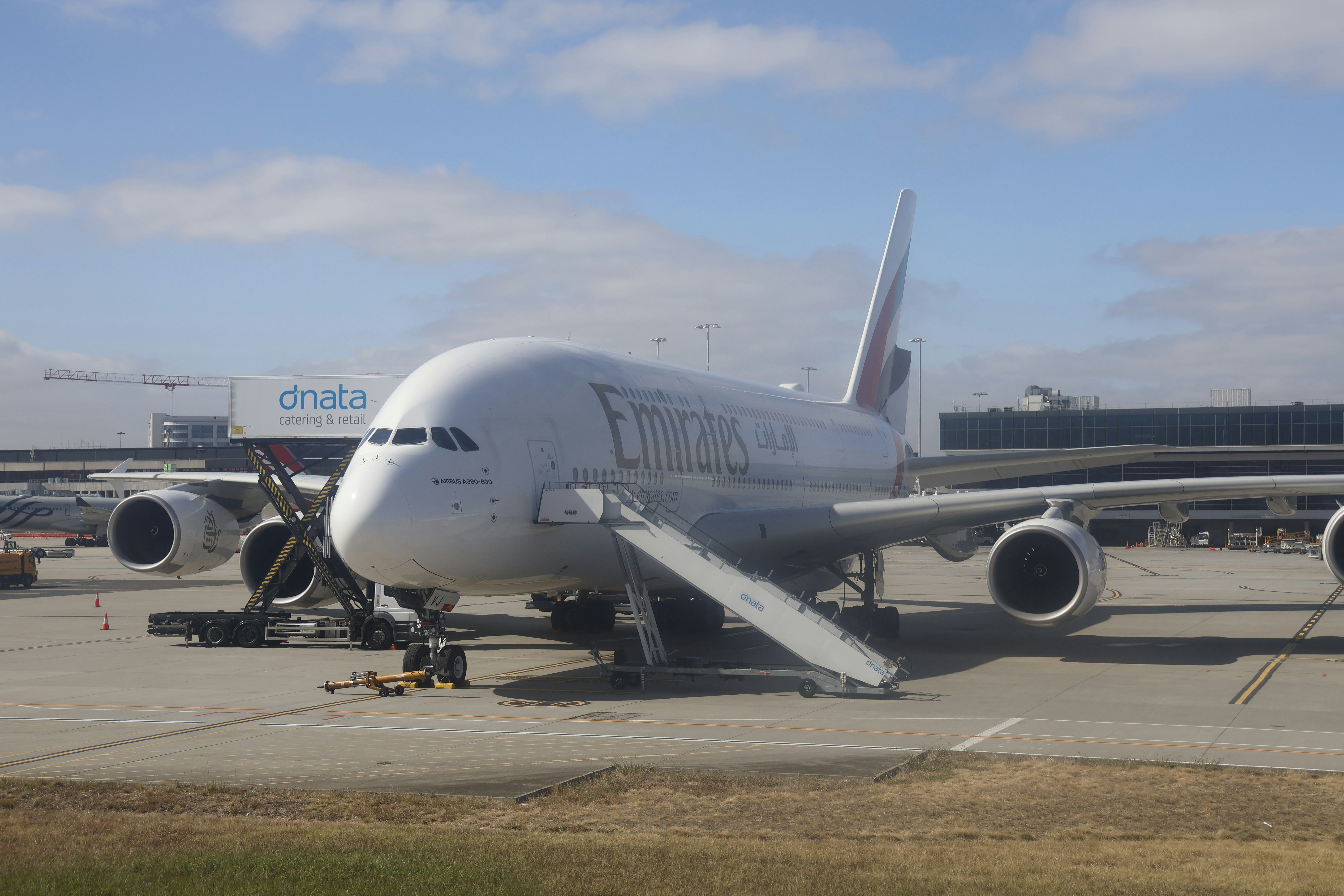 Airfield Giant: Emirates A380 at the Gate with Ground Equipment in Quiet Dawn