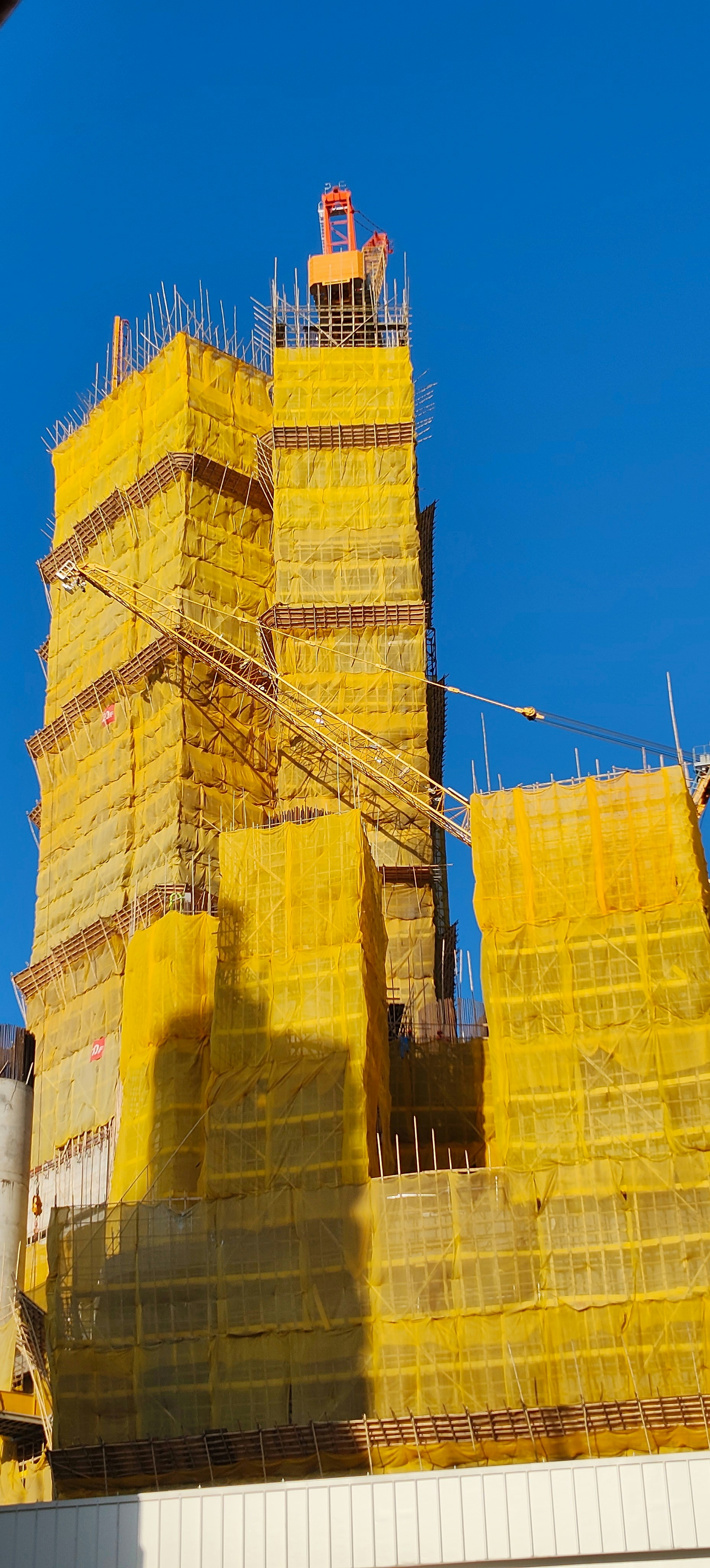 Tall building under construction covered in yellow netting.