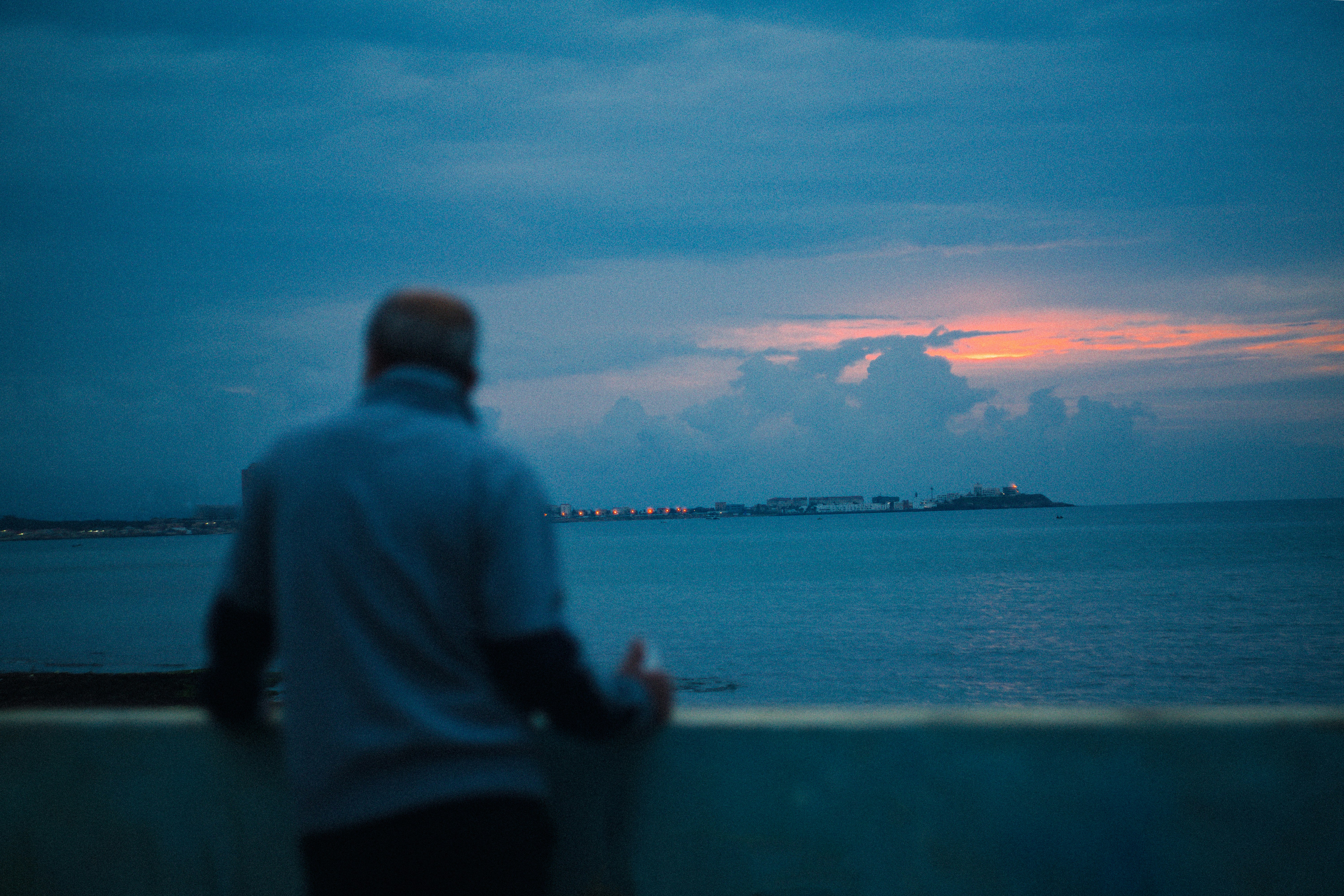 Evening by the Pier: A Blur of Distant Lights and a solitary figure
