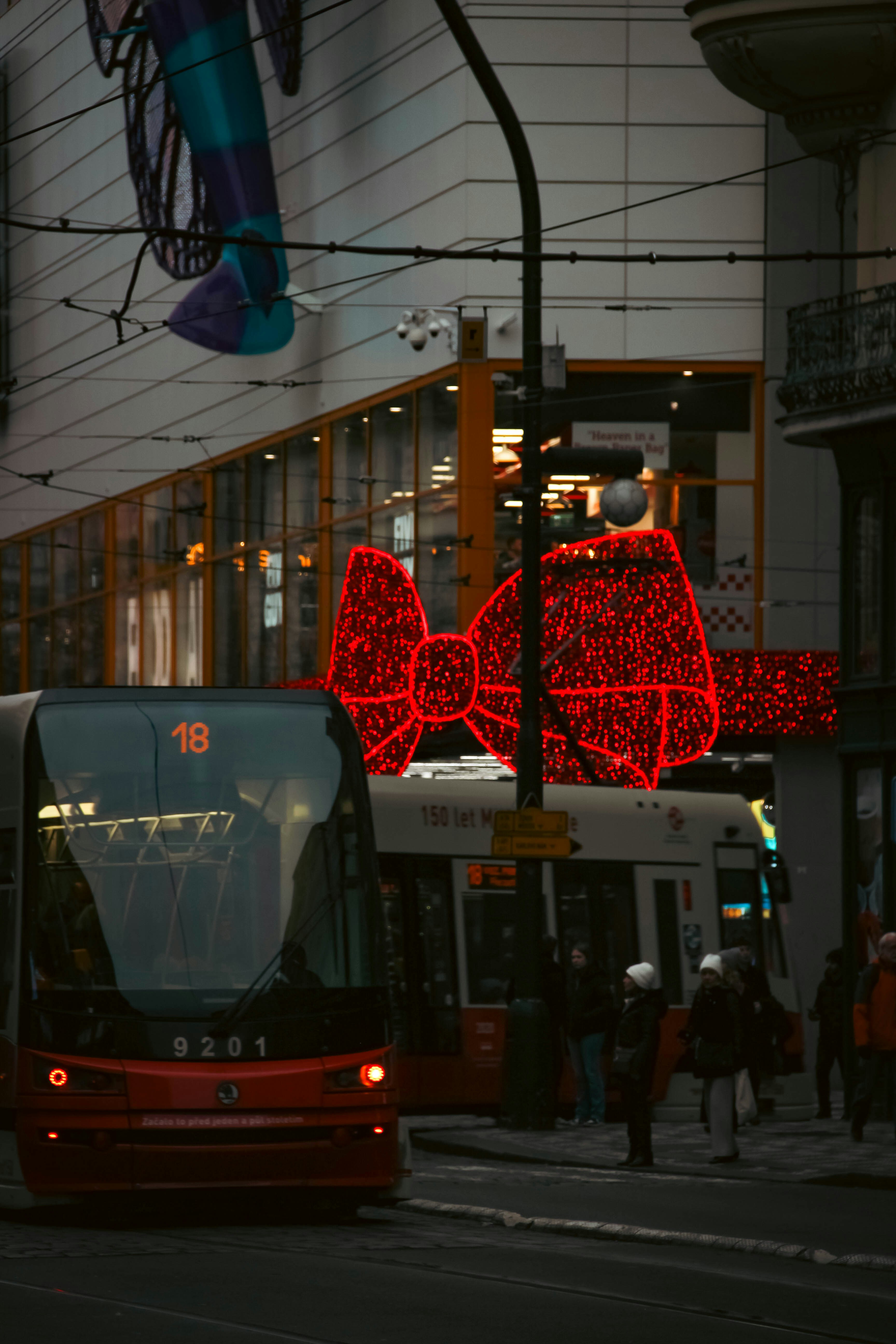 Neon Bow and Tram Currents: A Festive Street Moment