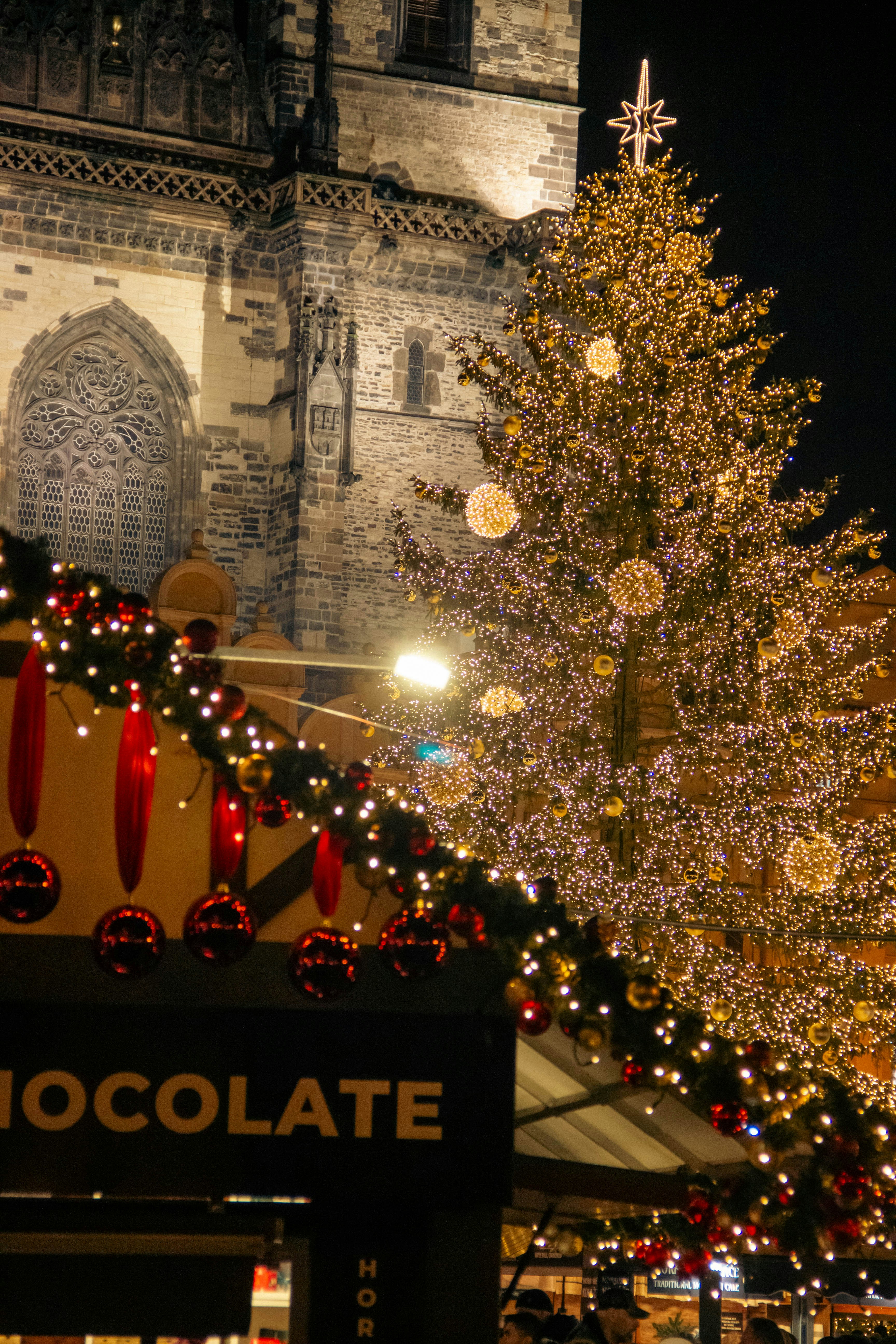 Festive Glow: A Night Market Beneath a Stately Gothic Facade