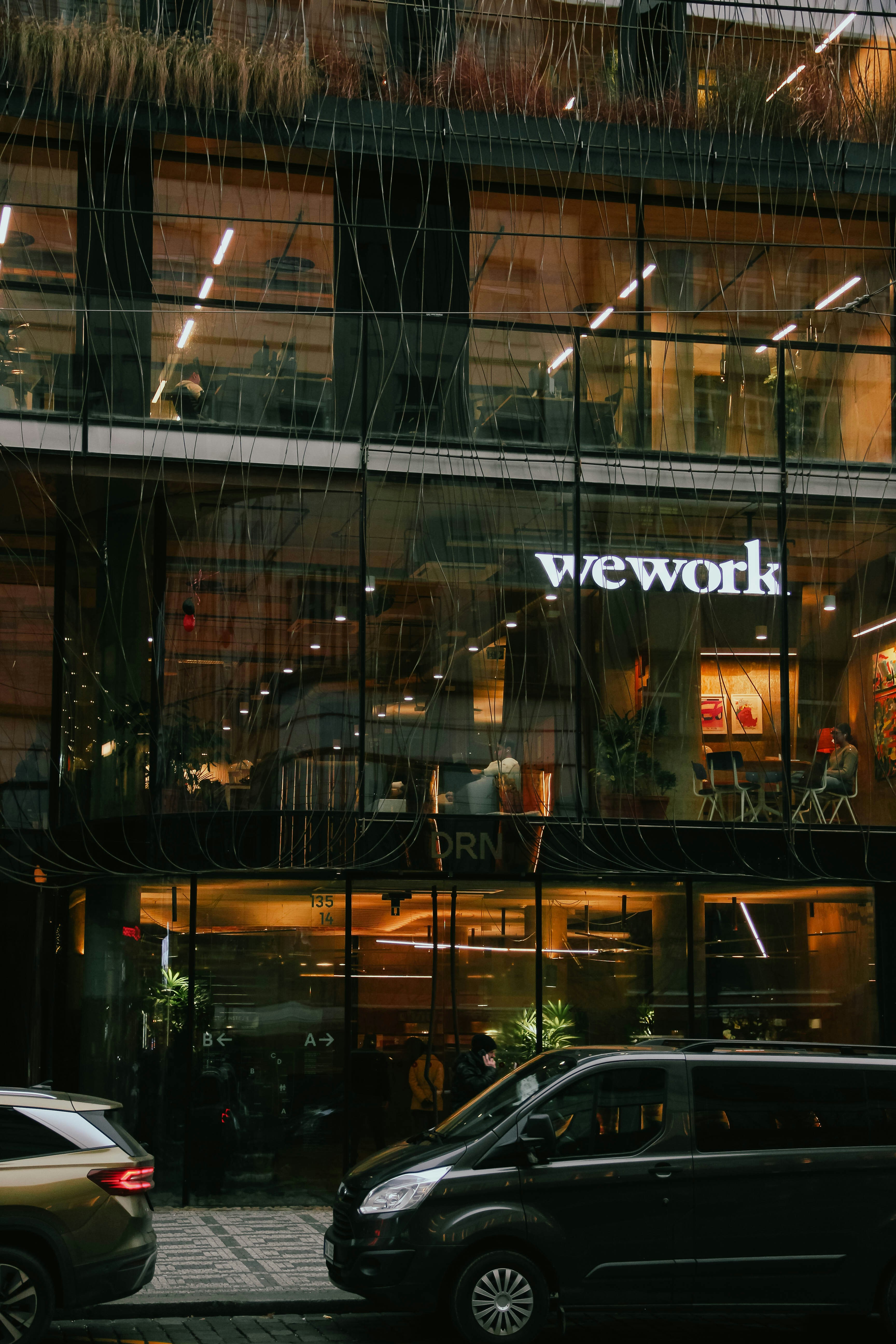 Neon Weave: A WeWork Facade Framed by Cables and City Traffic