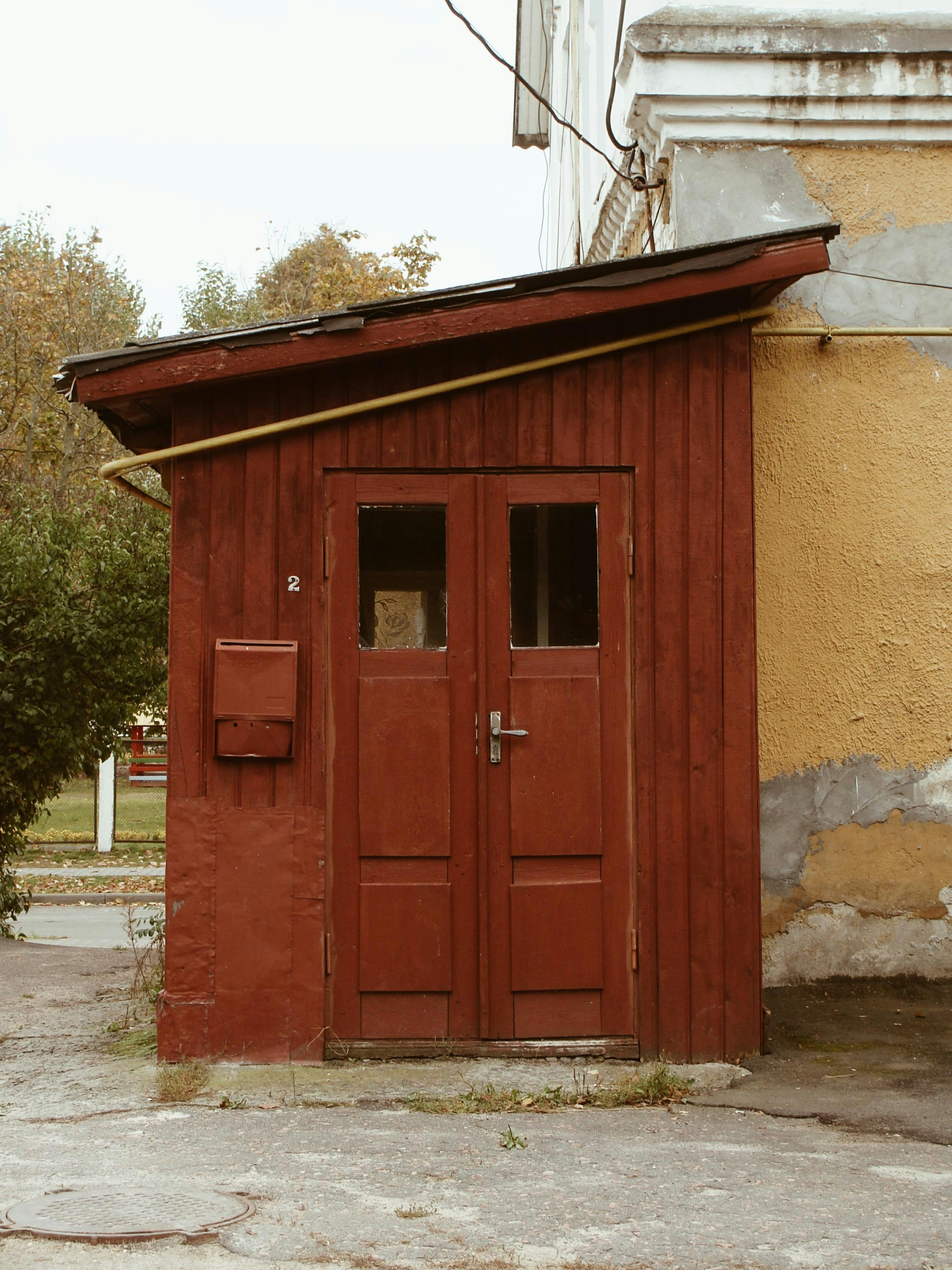 Weathered Red Doorway Beneath a Faltering Roof