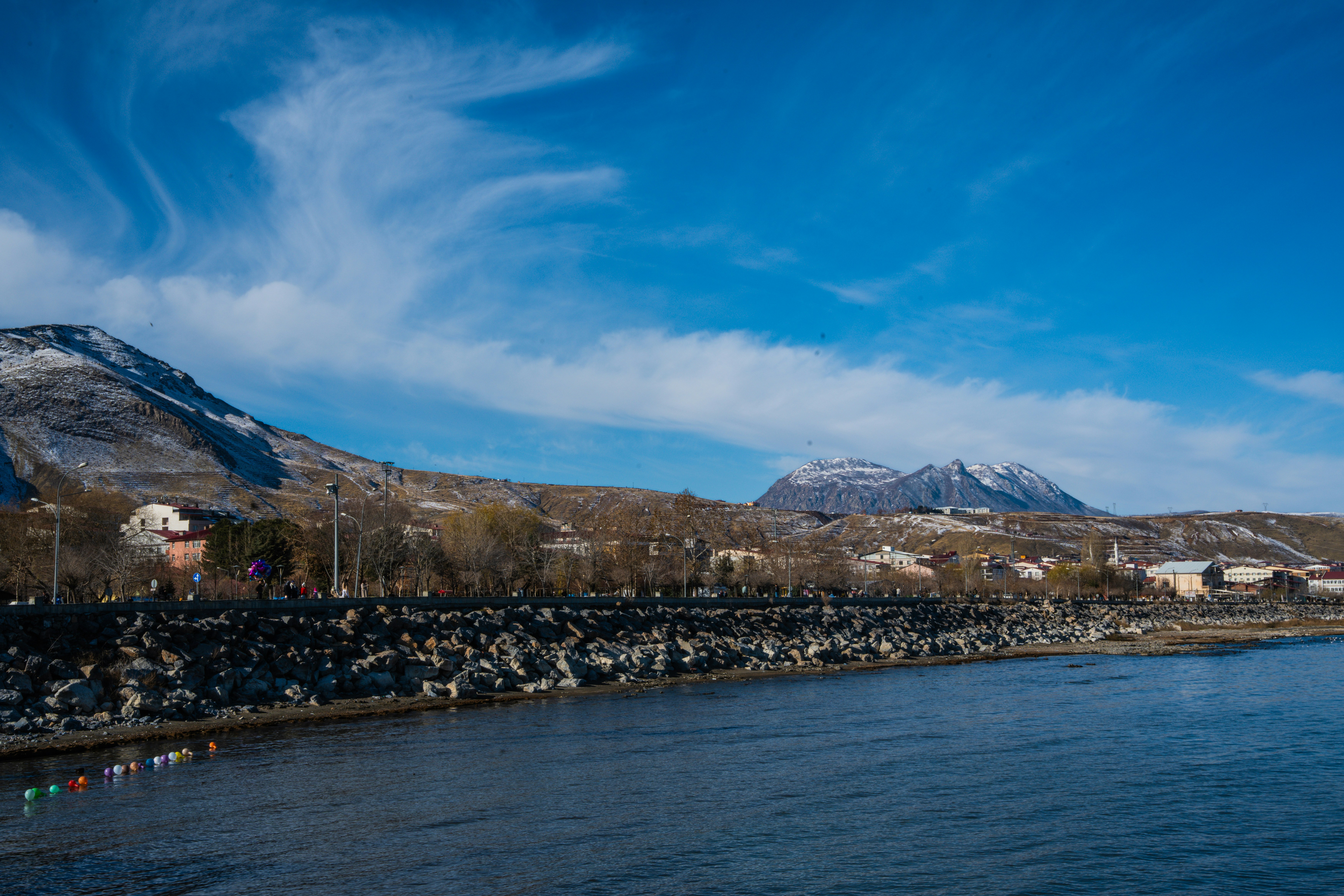 Coastal town at the edge of snow-kissed hills under a bright blue sky