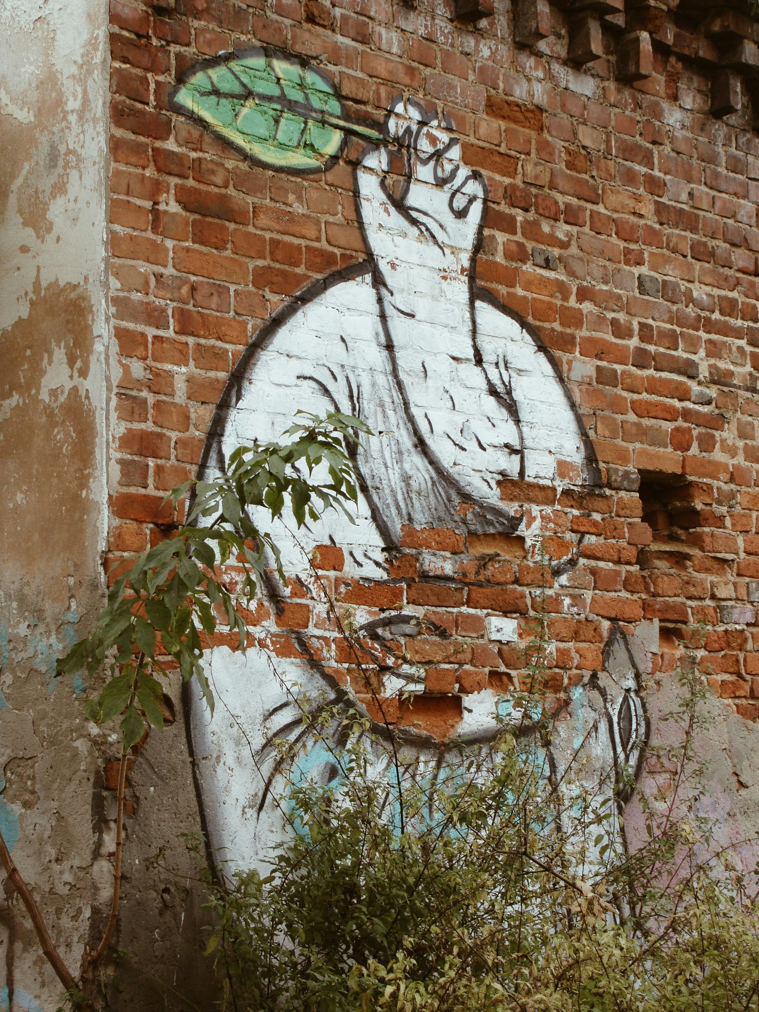 Graffiti Hand with Leaf on Weathered Brick Face