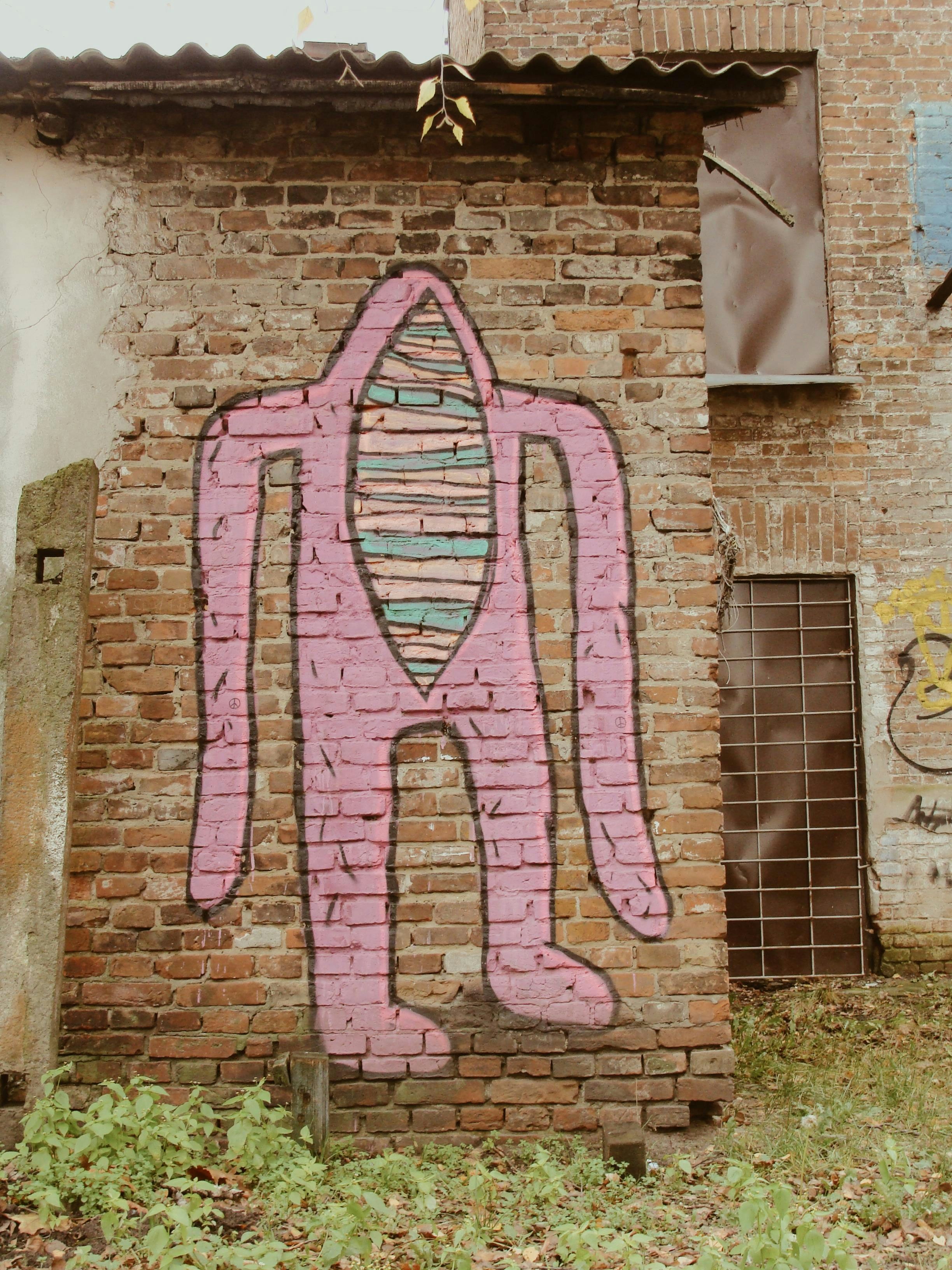 Pink graffiti figure on a weathered brick wall