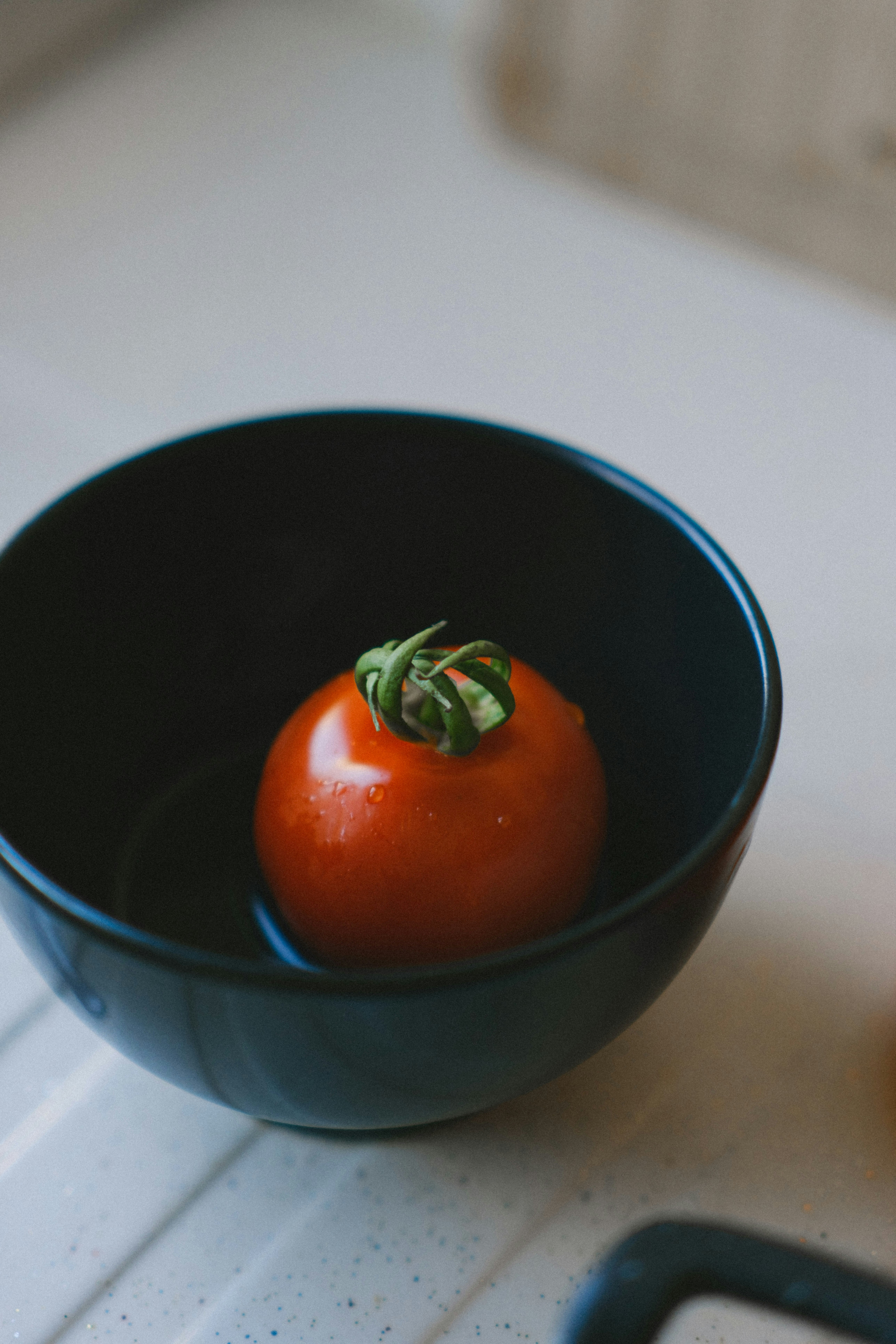Single Cherry Tomato in a Matte Black Bowl
