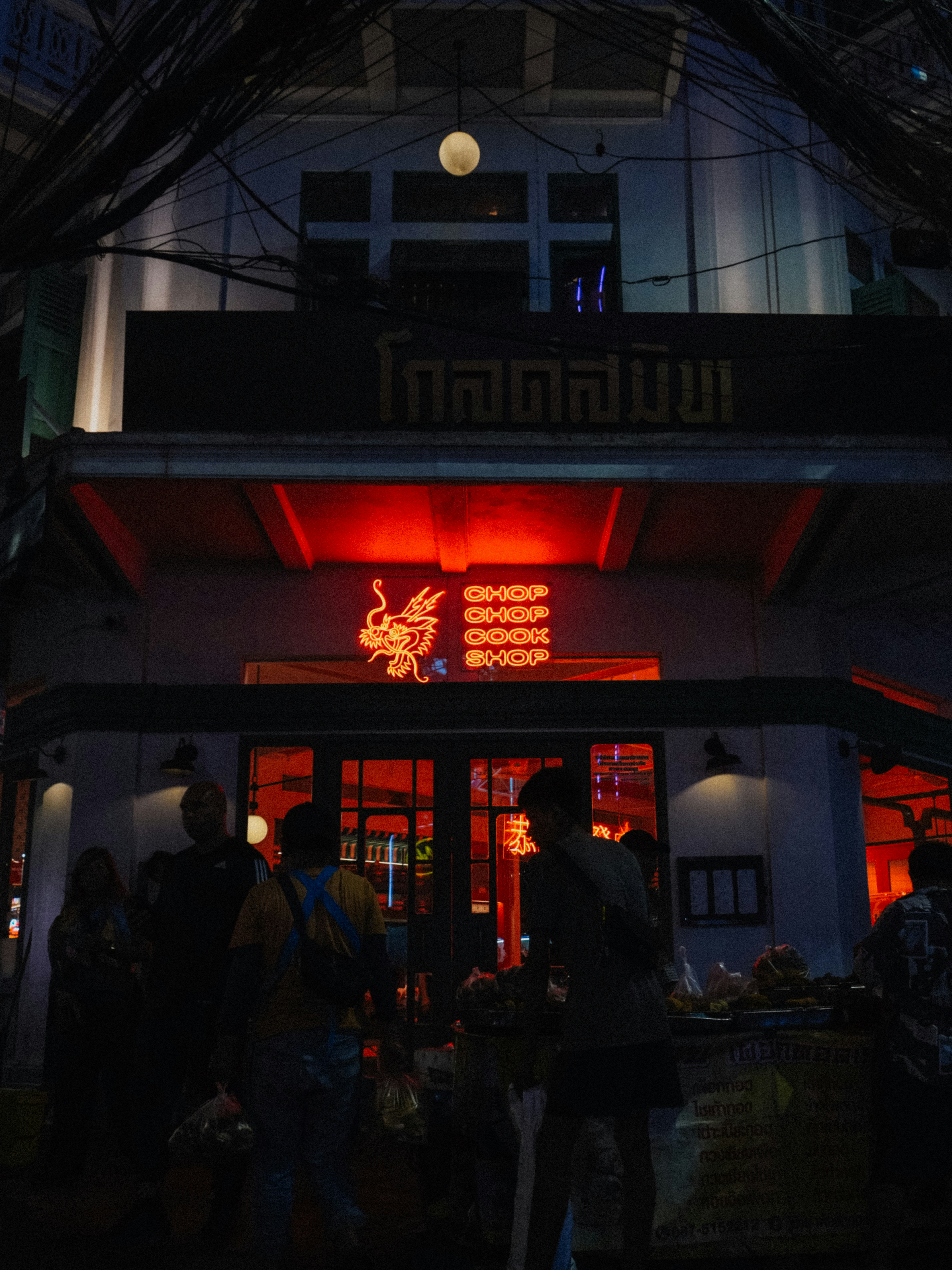 Neon Sign and Silhouettes at a Dimly Lit Shopfront