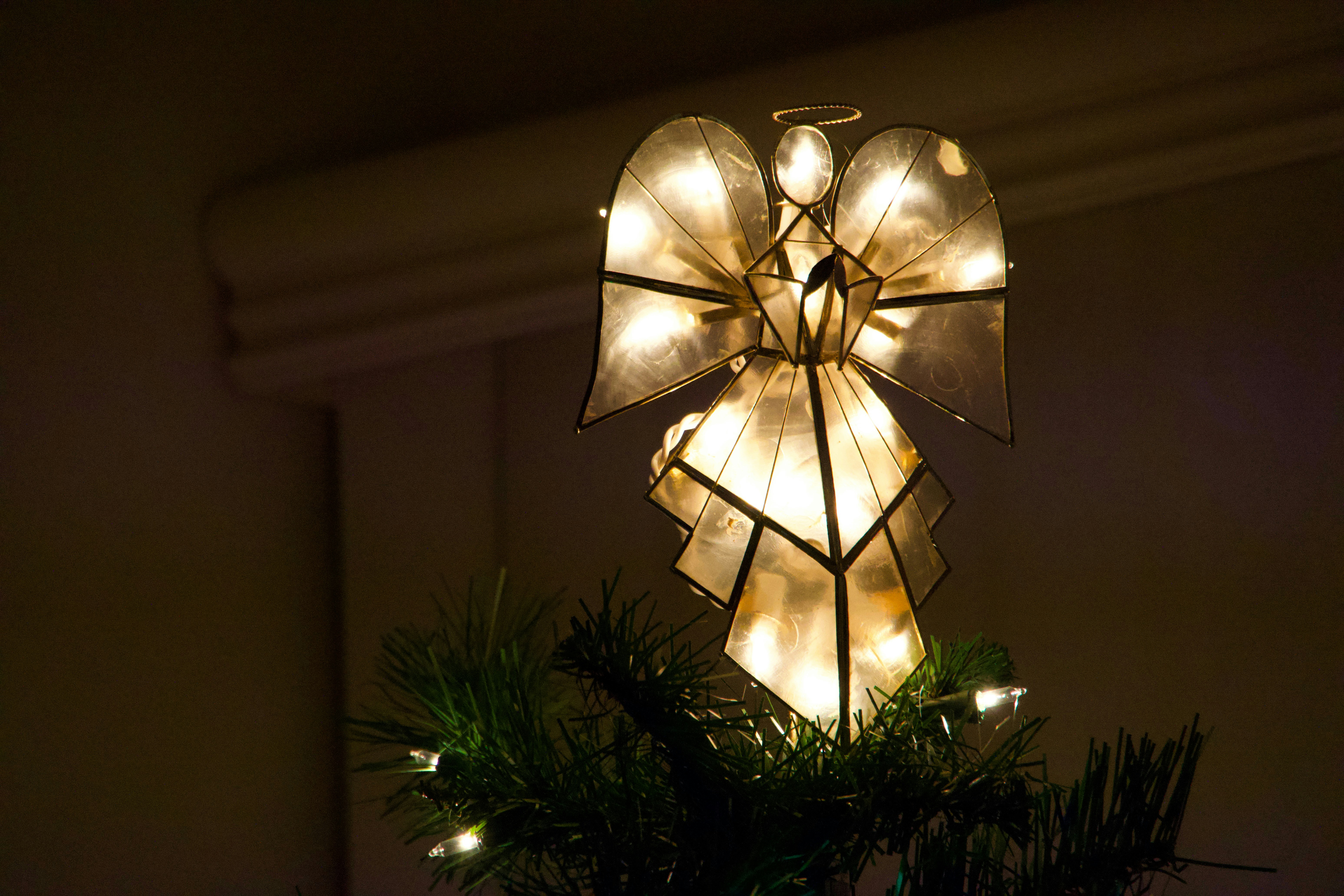 Glowing angel on a fir: a warm, sculpted light atop a Christmas tree