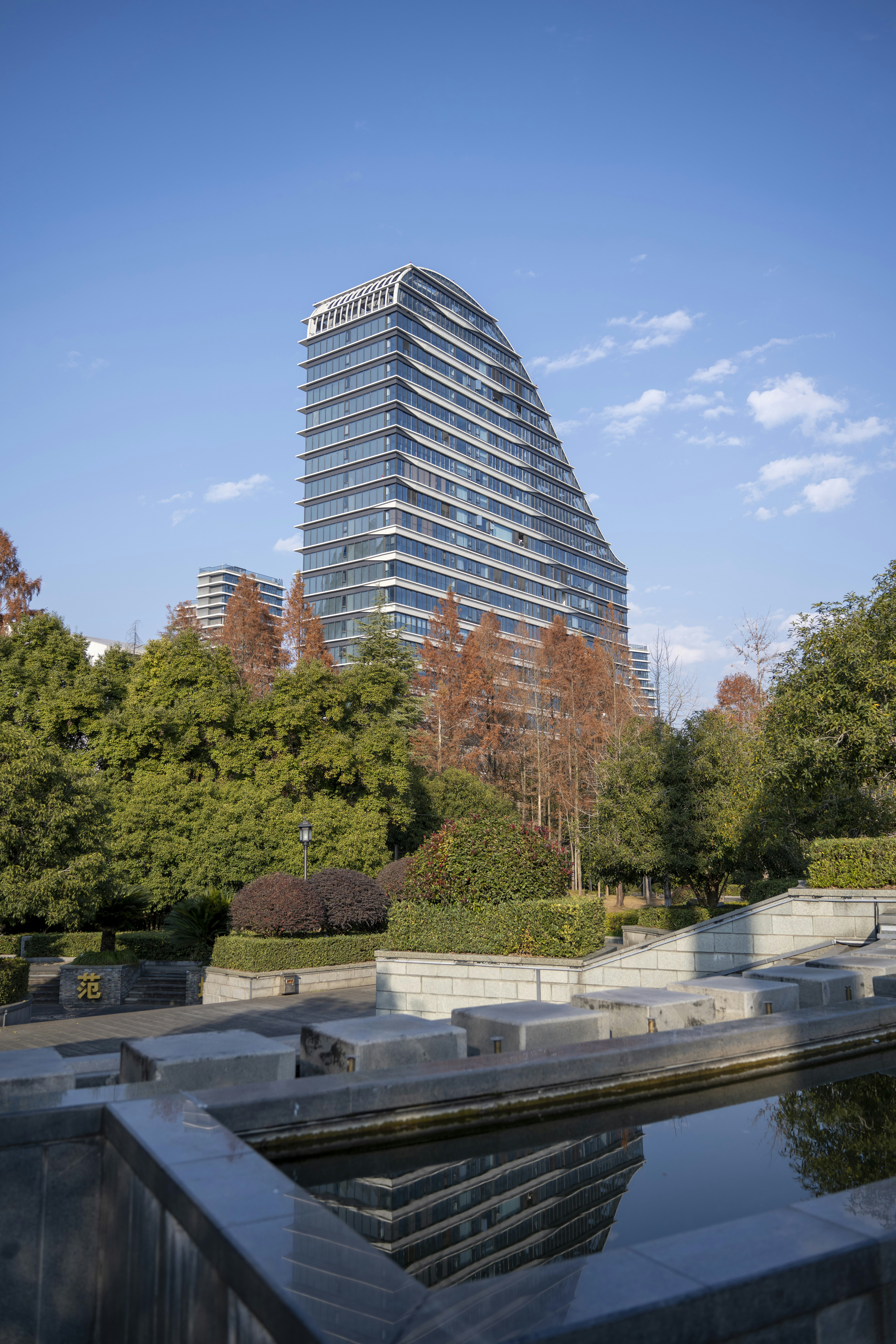 Towering Glass Arc: Urban Skyline Rises Above Autumn Park