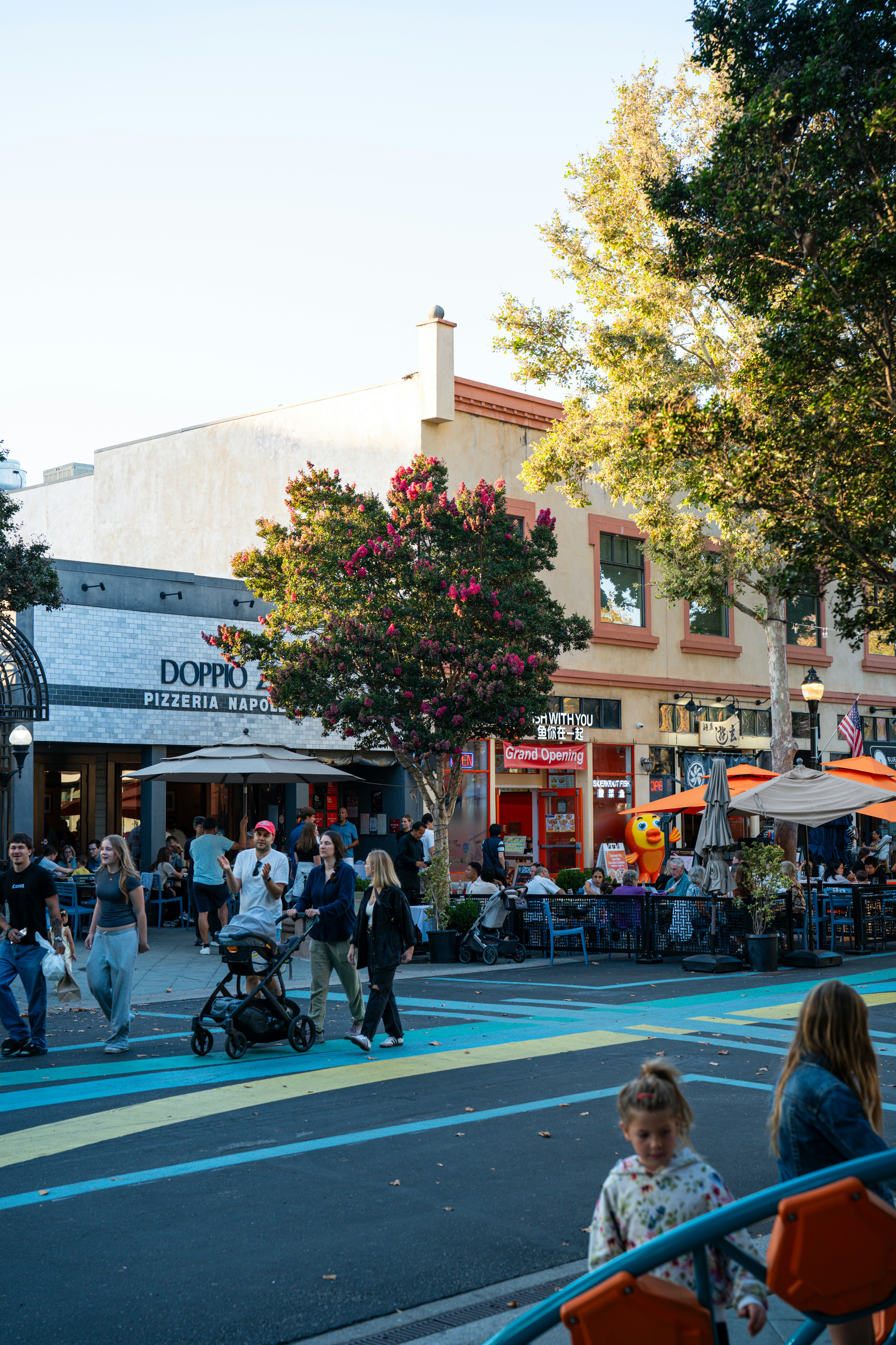 Sunlit Street Café Crowd under Blooming Treefront