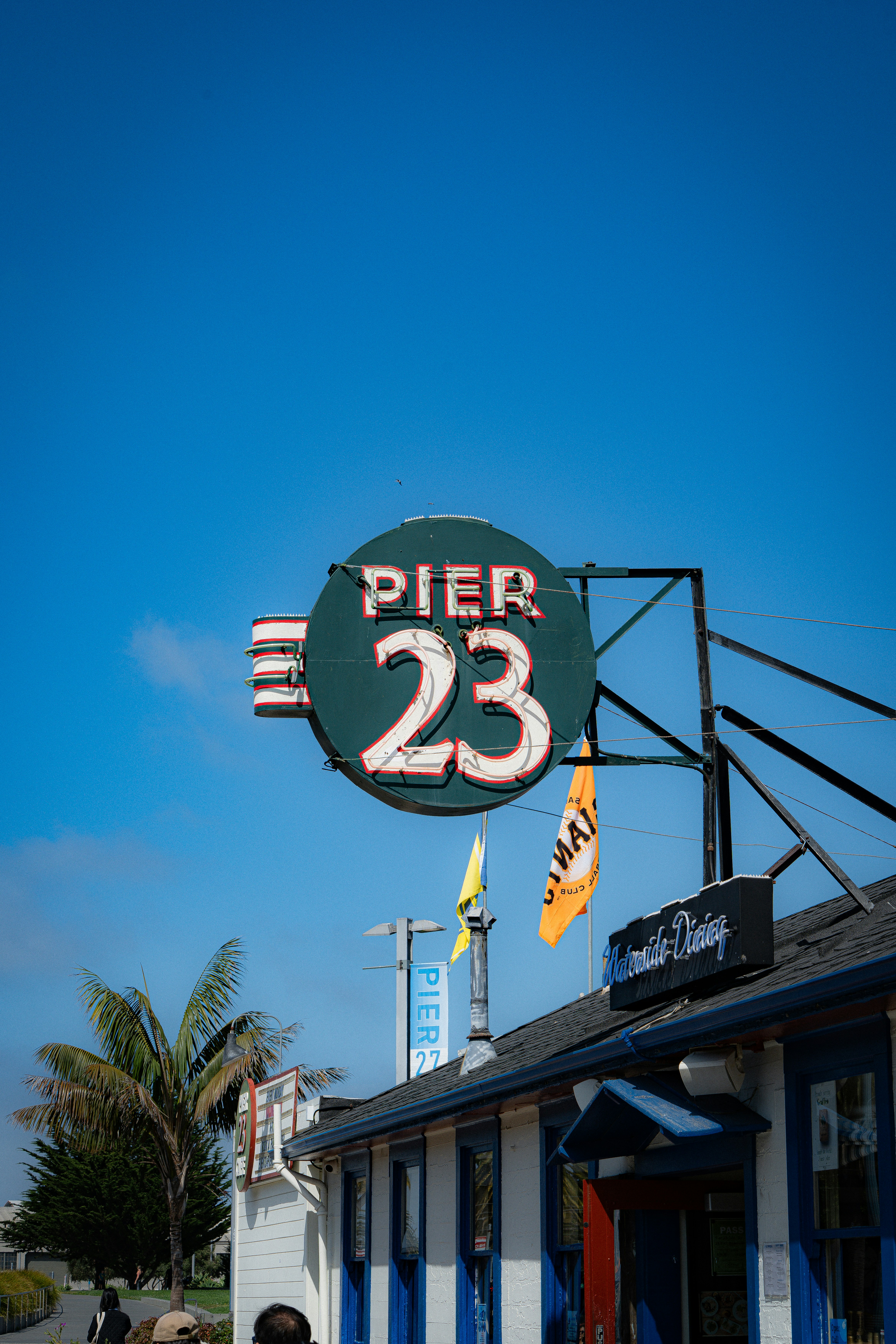 Pier 23 Neon Sign Above a Blue Oceanside Cafe