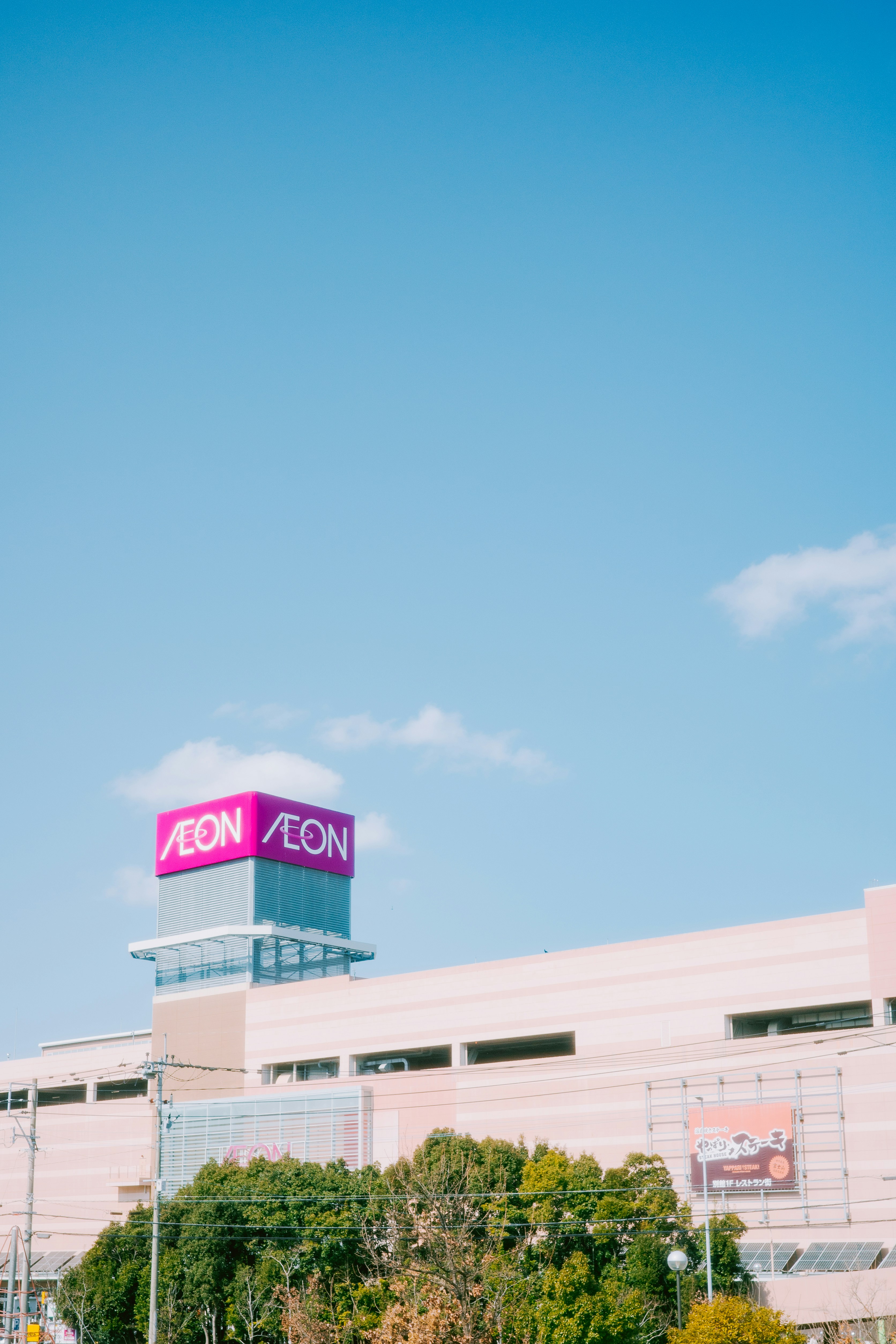 AEON Toweron Blue: Minimal Sky Above a Peach-toned Mall Complex