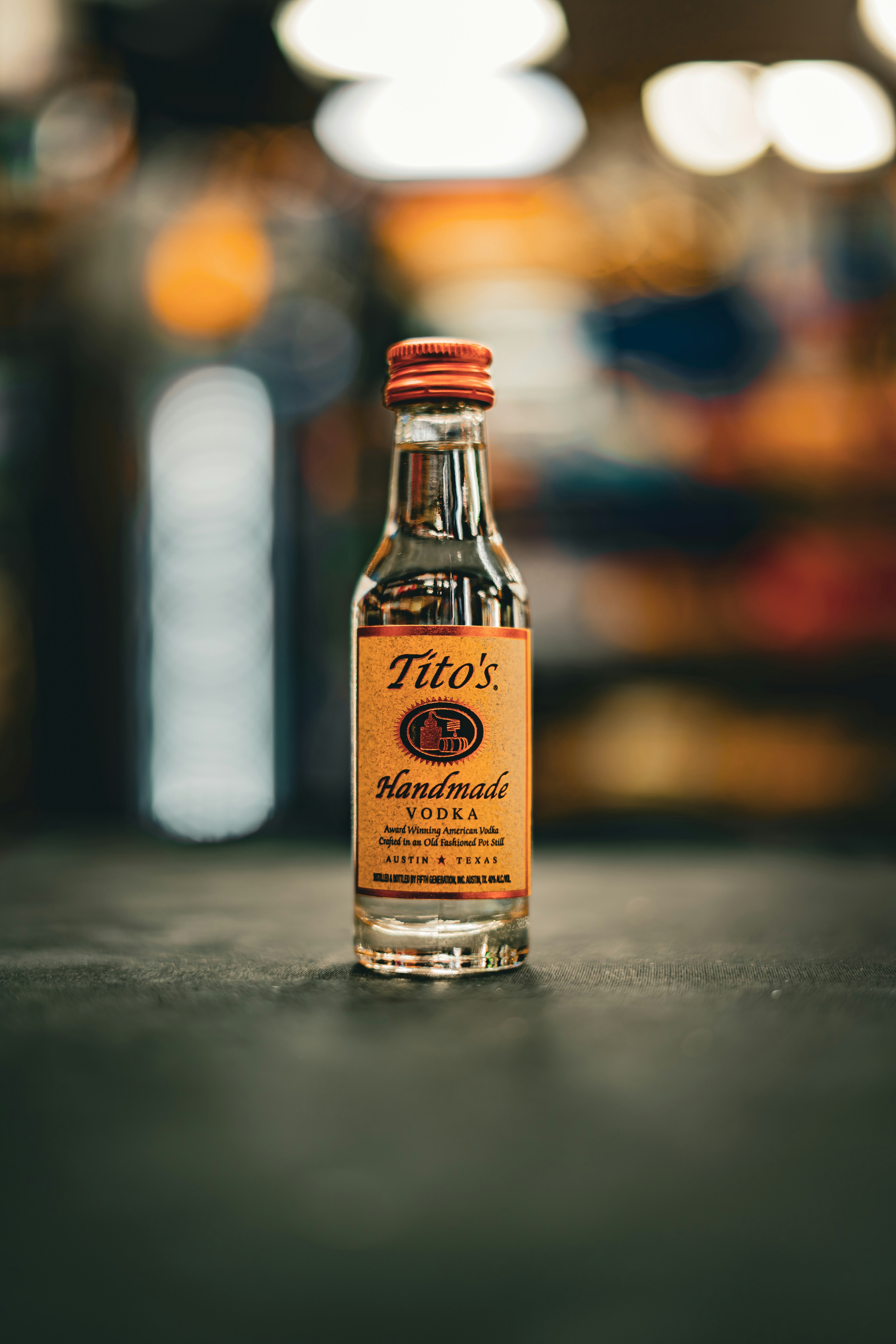 Single Bottled Focus: Tito's Handcrafted Vodka on a Dim Bar Counter