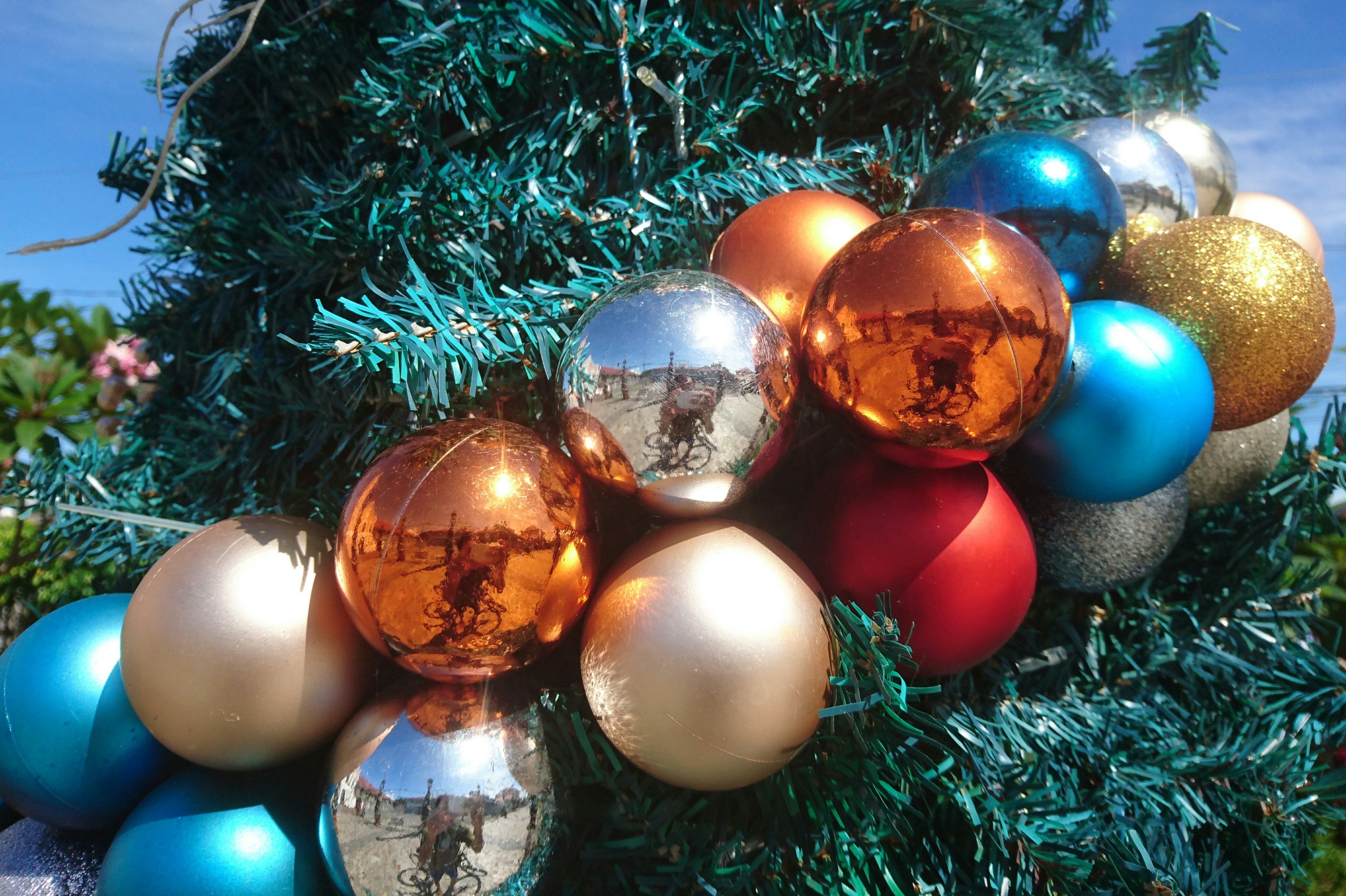 Colorful christmas ornaments on a blue tinsel tree