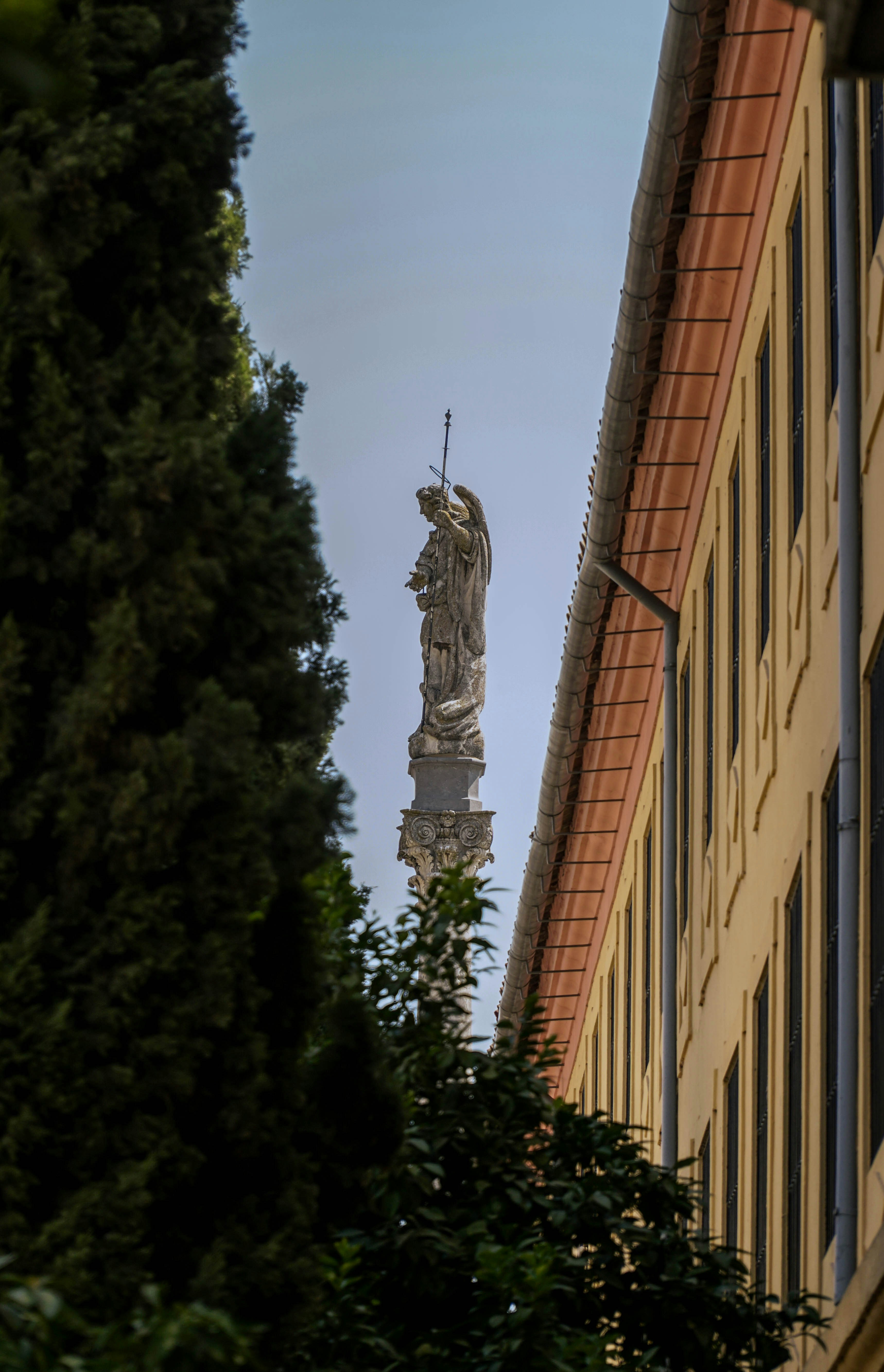 Statue Crowned Between Garden Shadows and Rooftops
