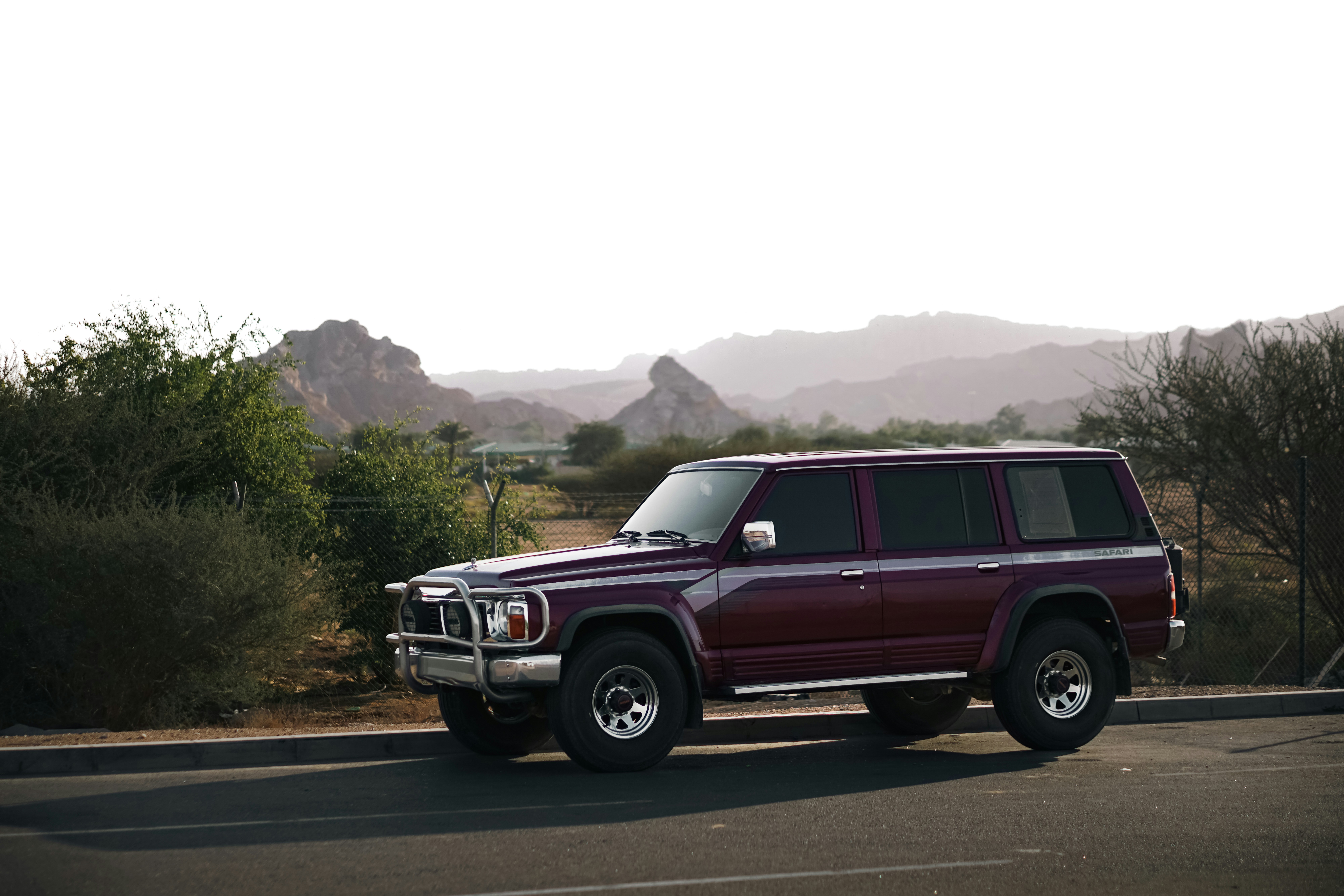Desert Road Warrior: A Maroon SUV Holds Ground At Sunset