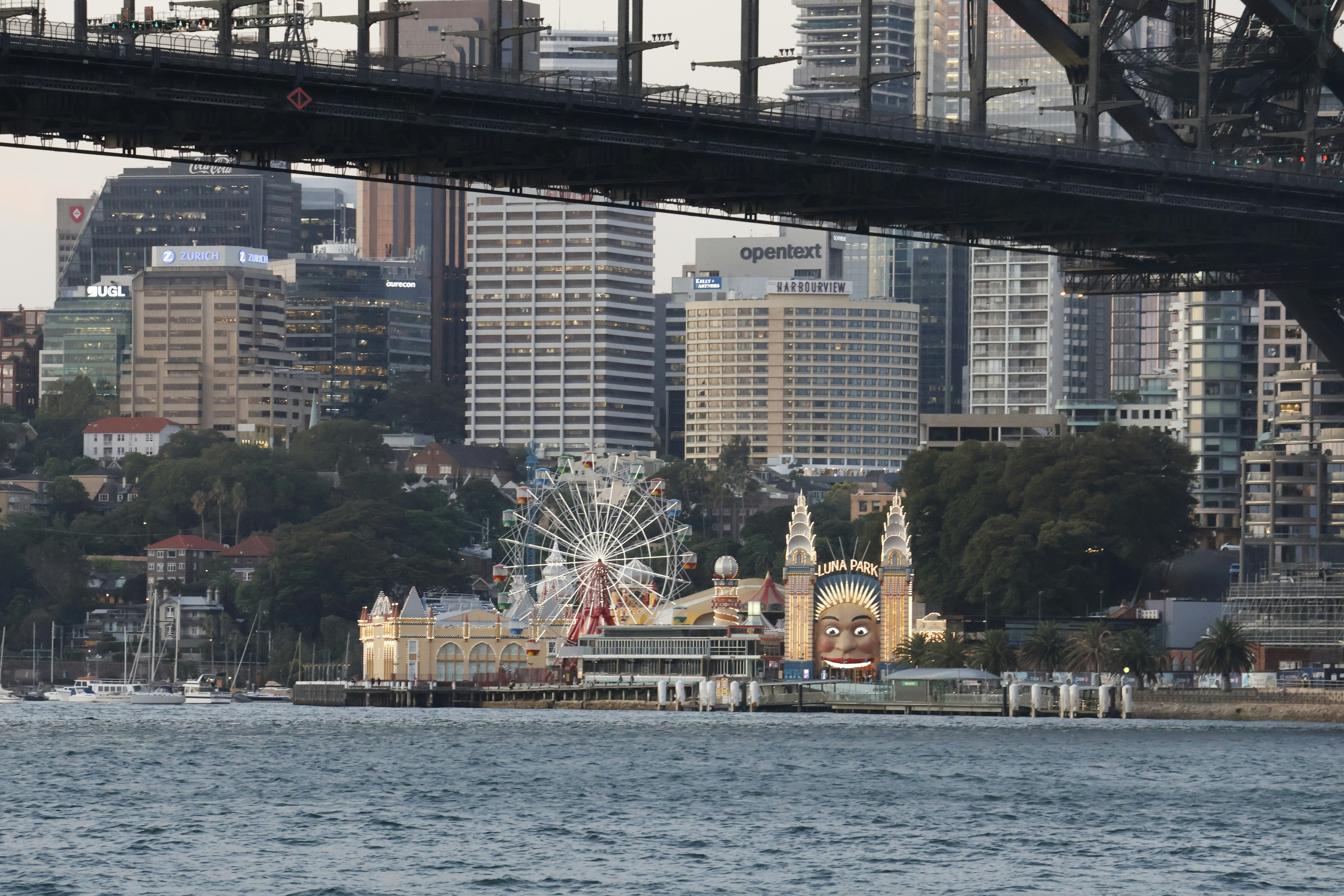 Cityscape on the Waterfront: Ferris Wheel, Lights, and Towered Structures Under a Bridge
