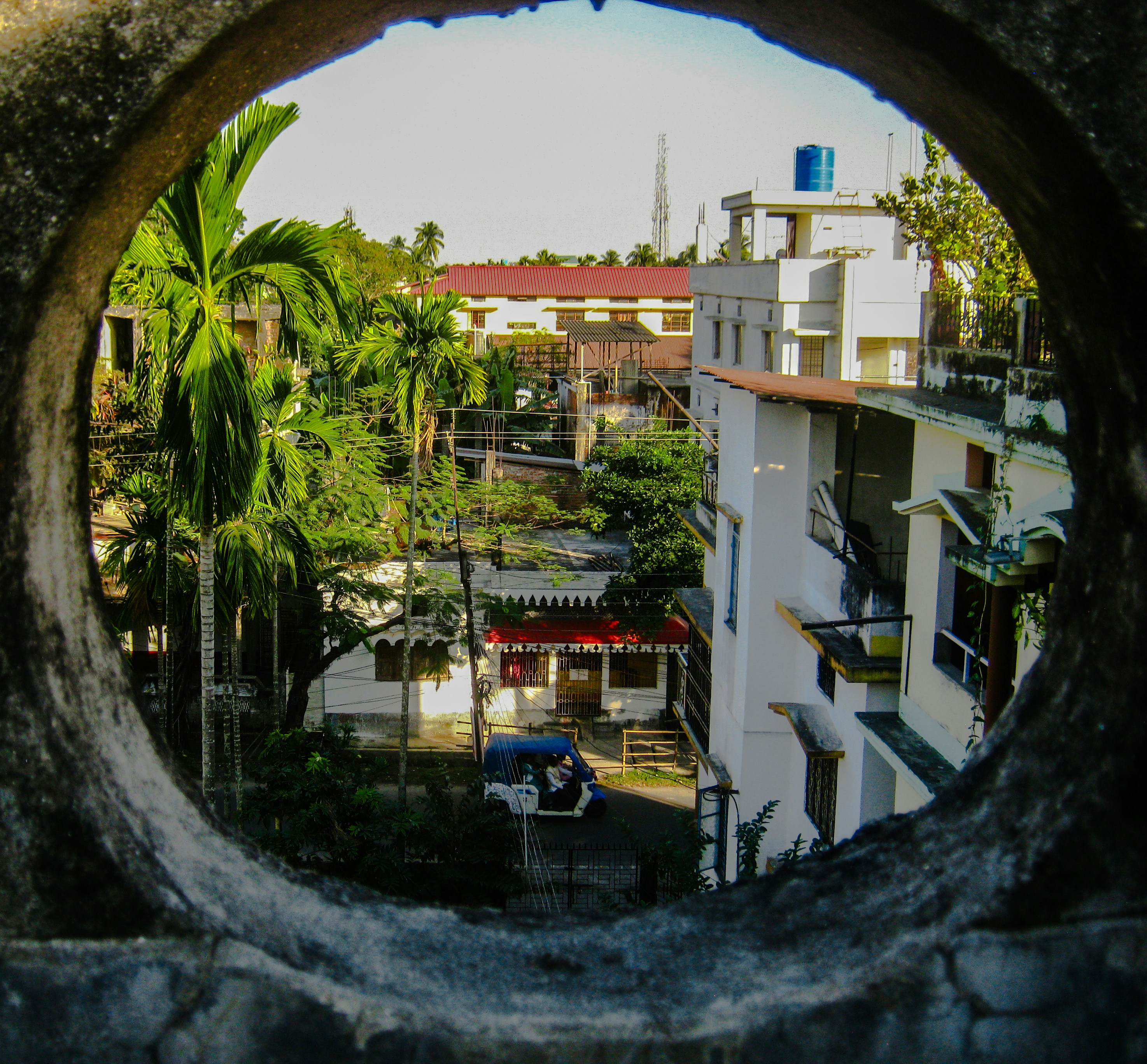 View of buildings and trees through a circular opening.