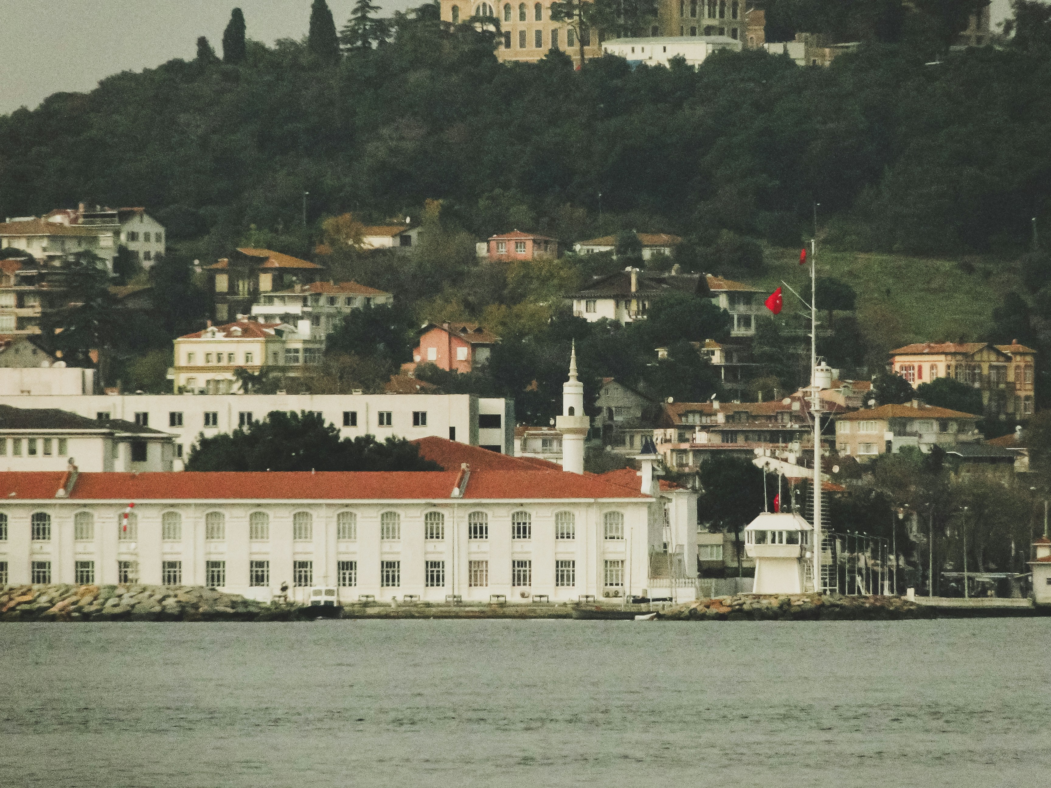 Buildings along a waterfront with a green hillside