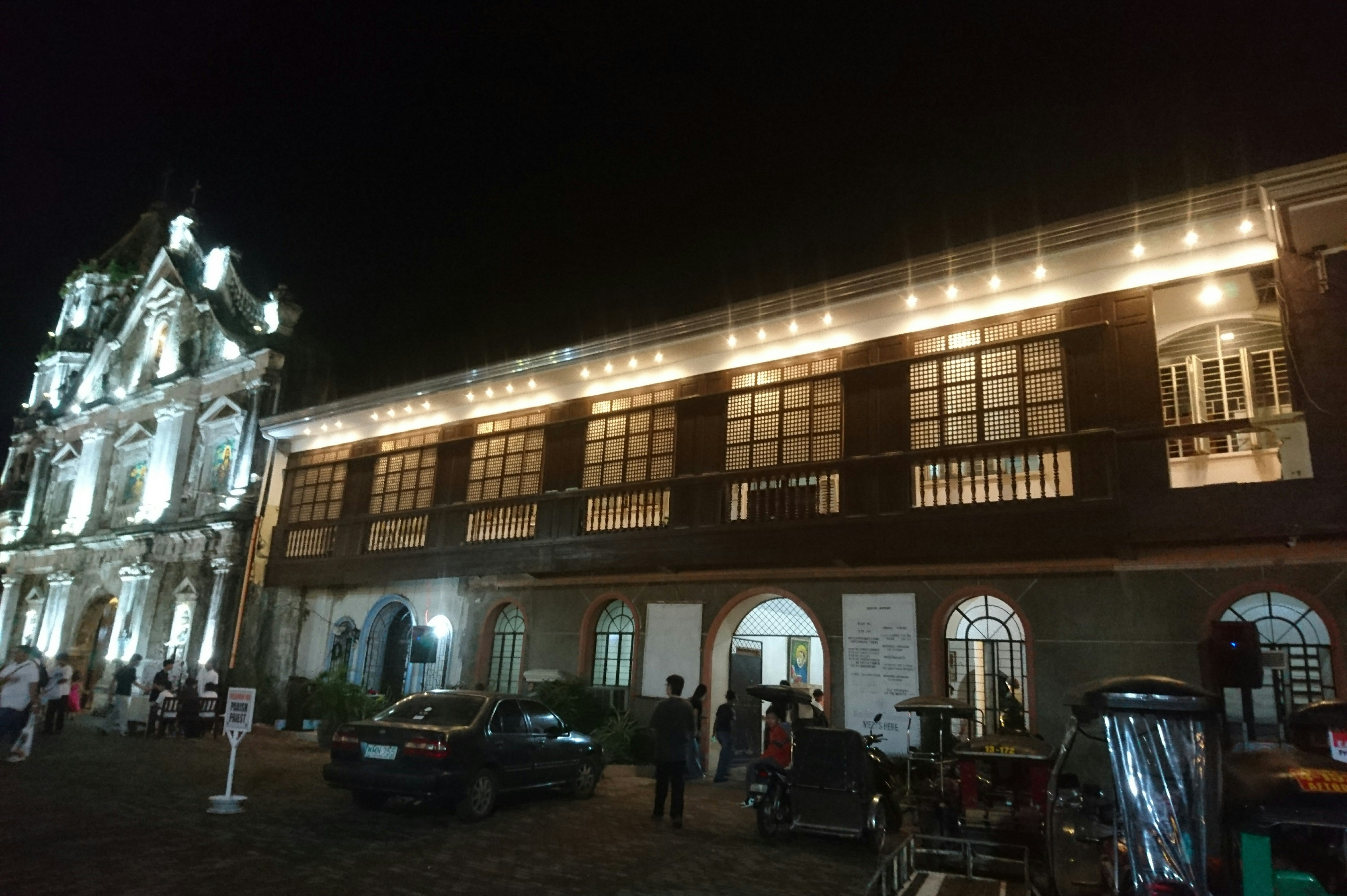 Ornate building illuminated at night with people outside