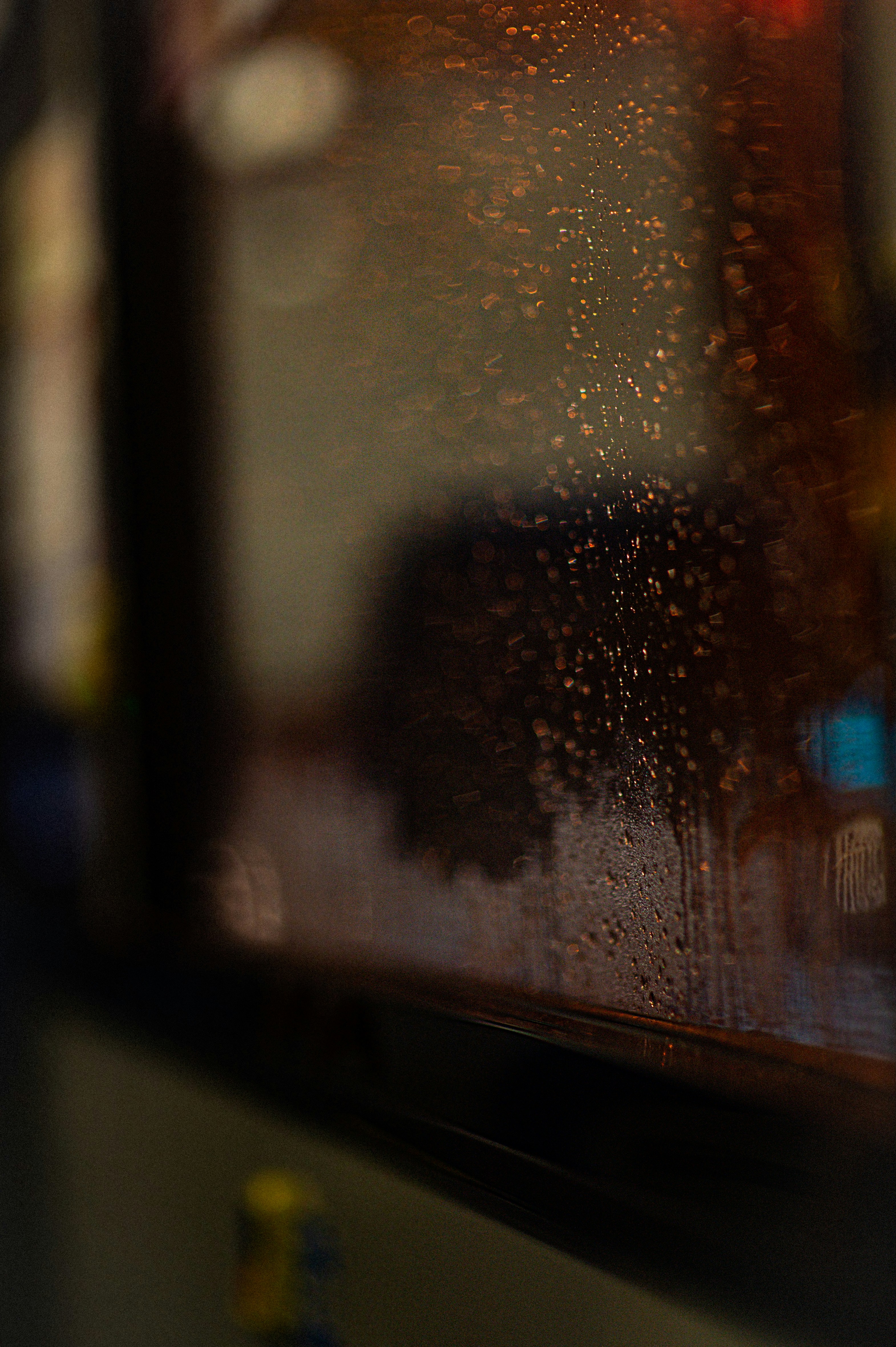 Moist Glass at Night: A Rain-Speckled Window in Soft Focus