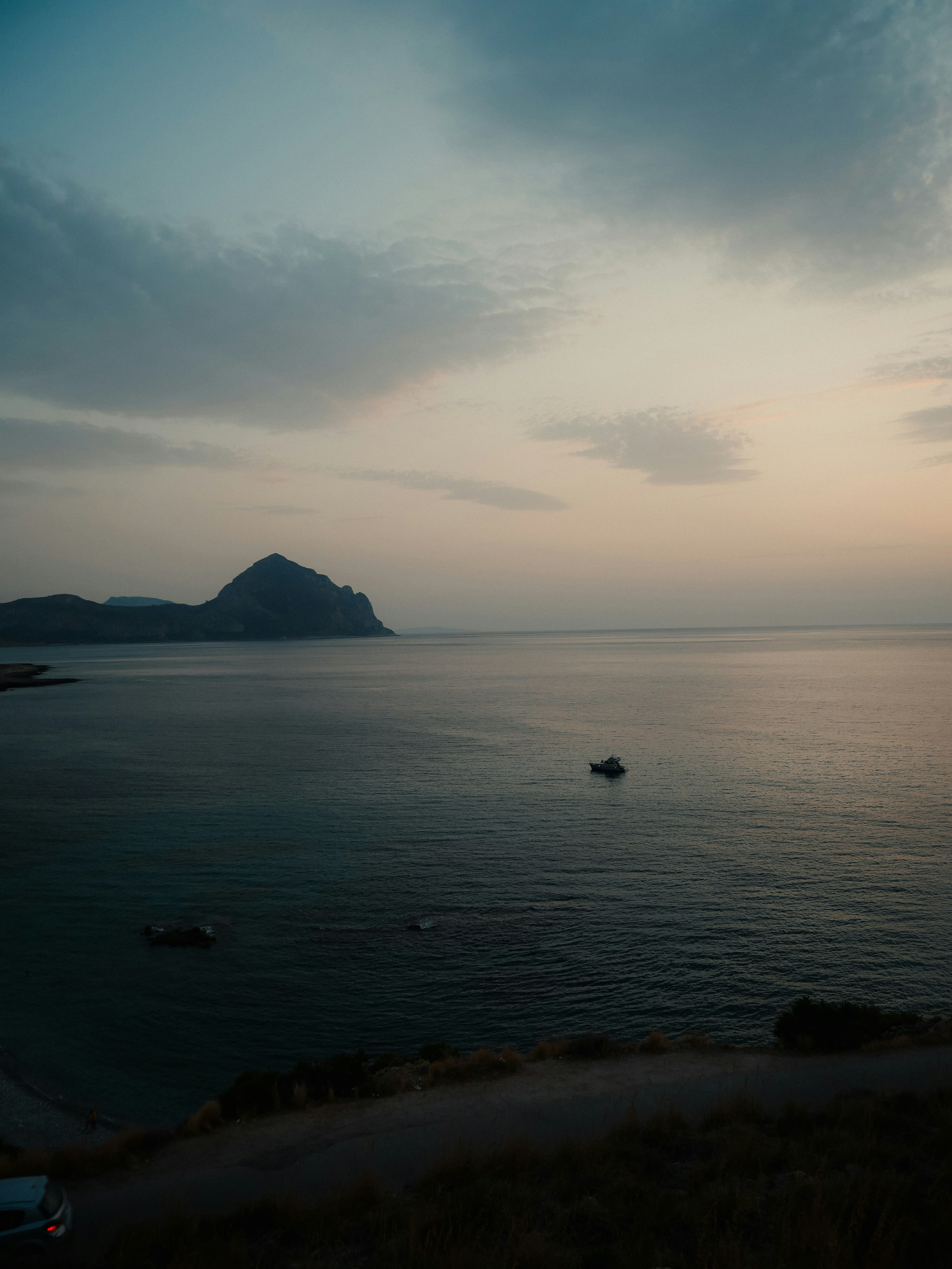 Quiet Horizon: A Sailboat at Dusk Near a Shadowed Island
