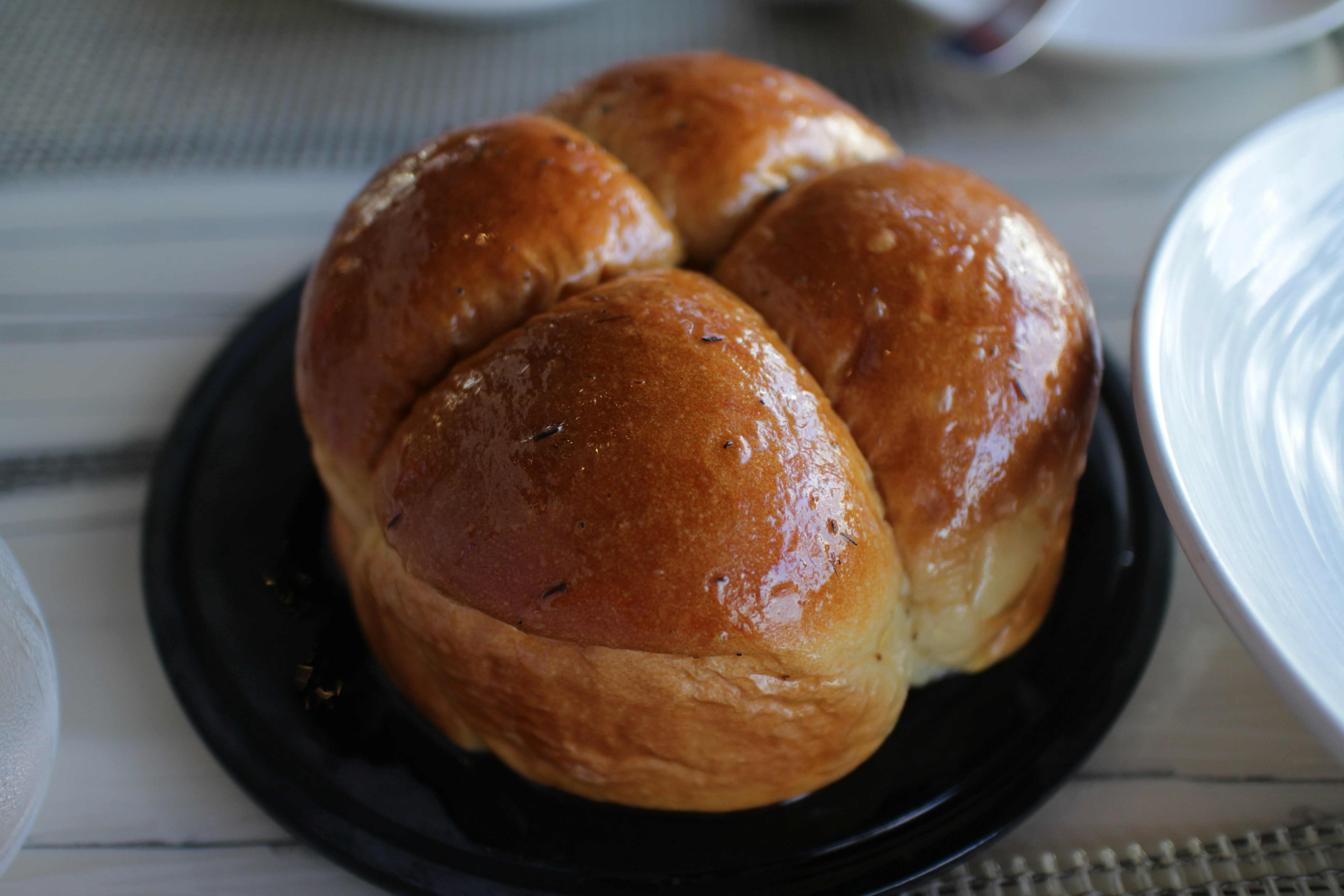 Golden brown braided bread roll on black plate