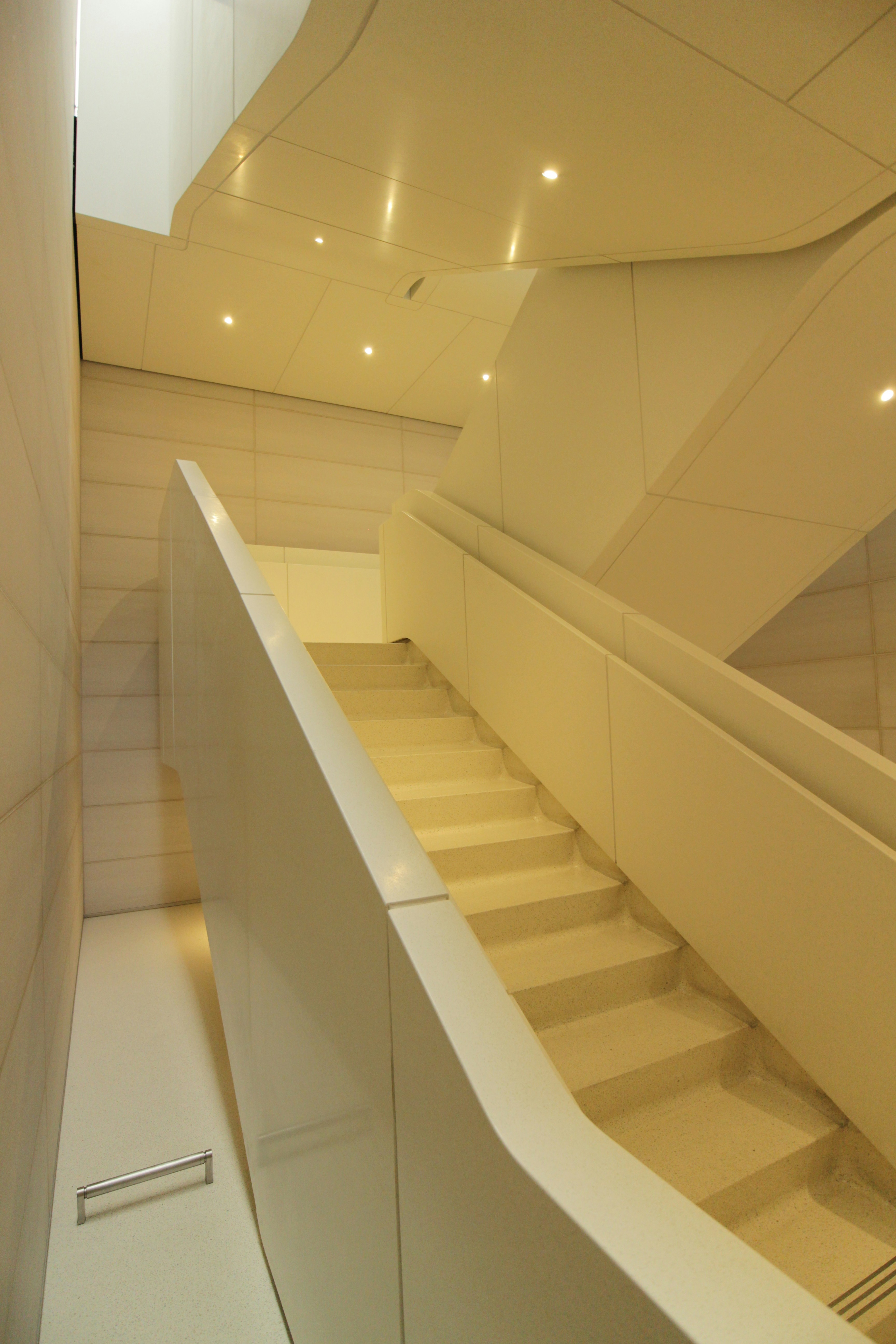 Modern white staircase with curved walls and ceiling.