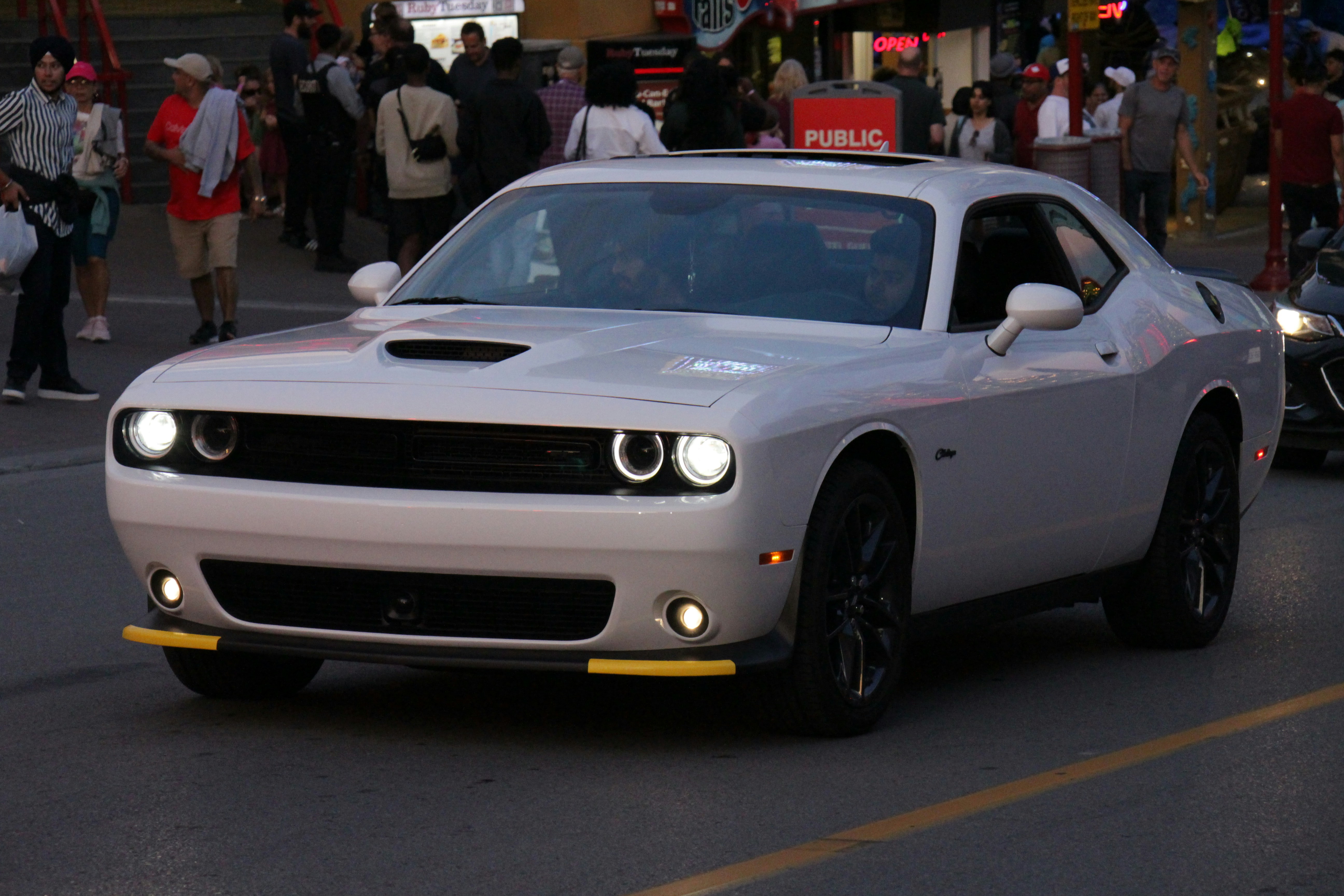 White dodge challenger driving on a street.