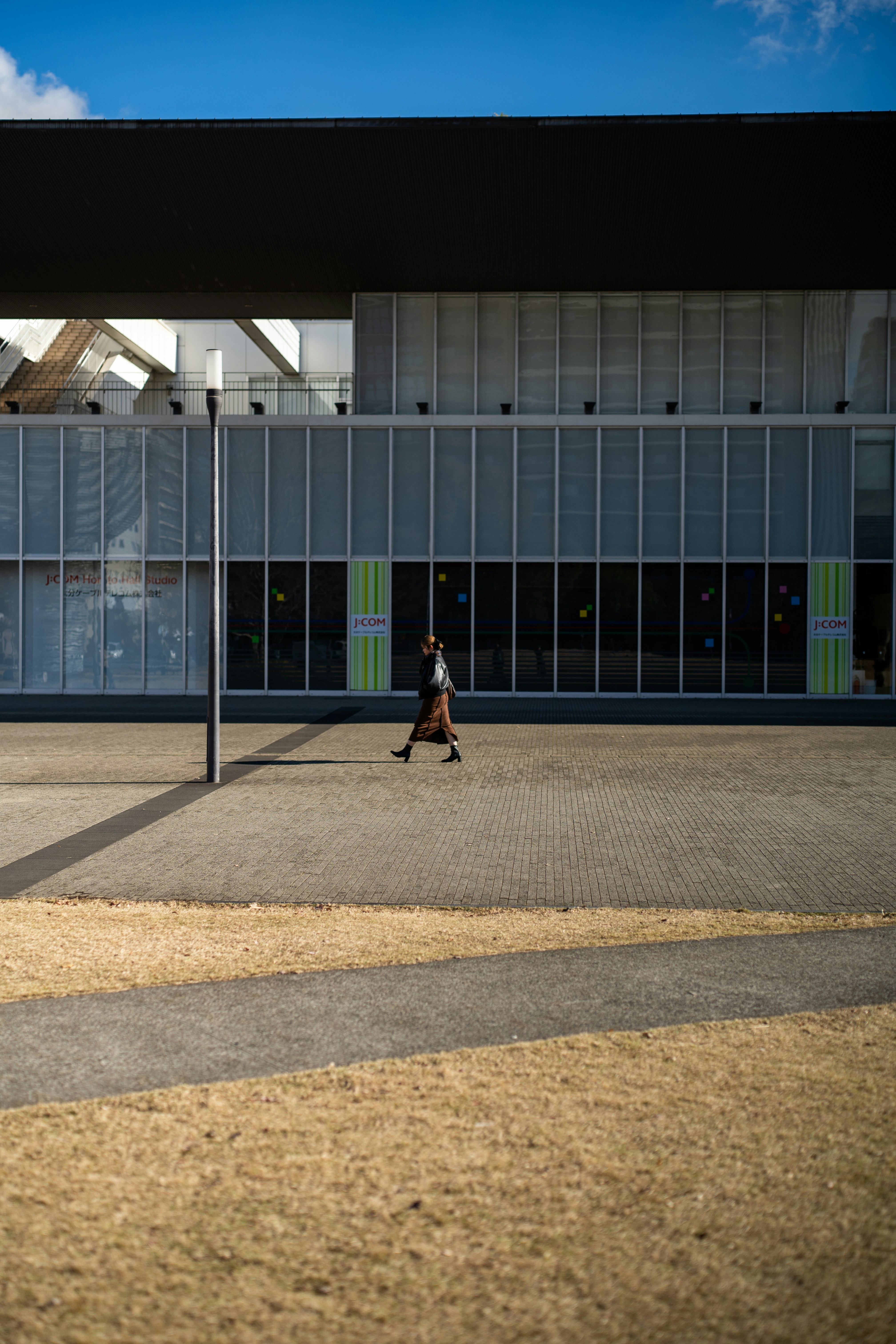 Pedestrian in Front of Modern Glass Facade at Dusk