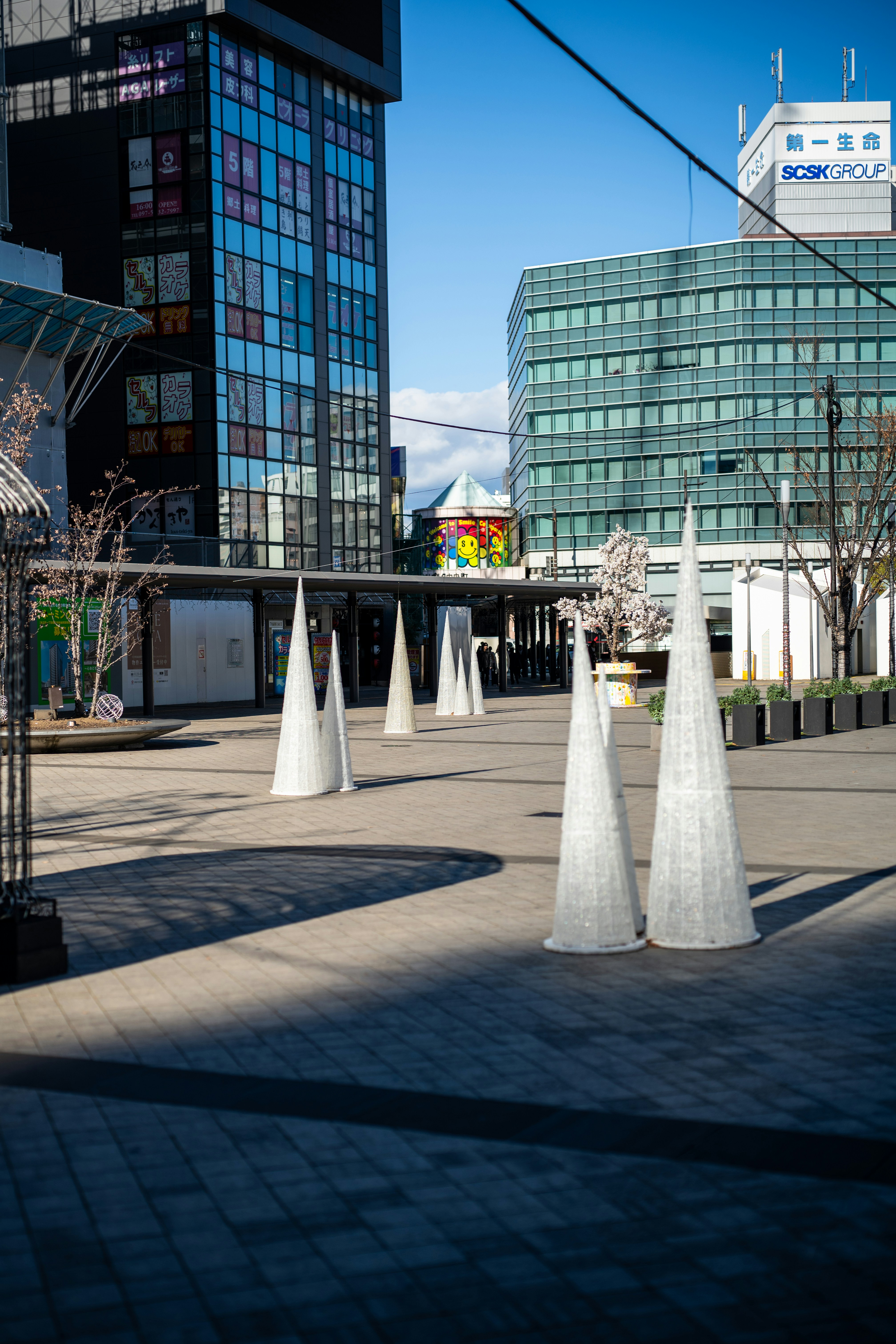 Urban plaza with cone sculptures under modern glass towers